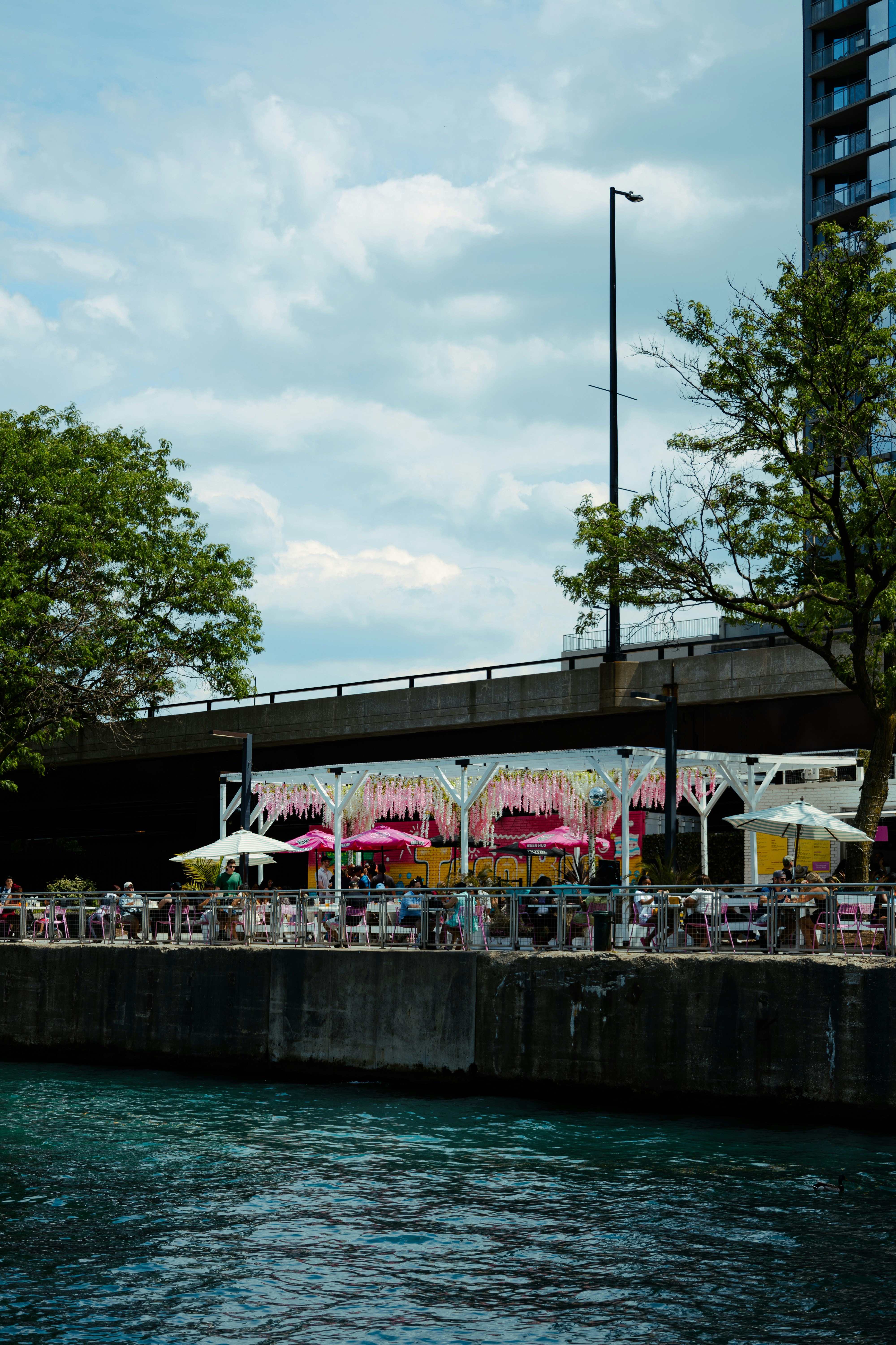 A group of people sitting at tables next to a river photo – Free City ...