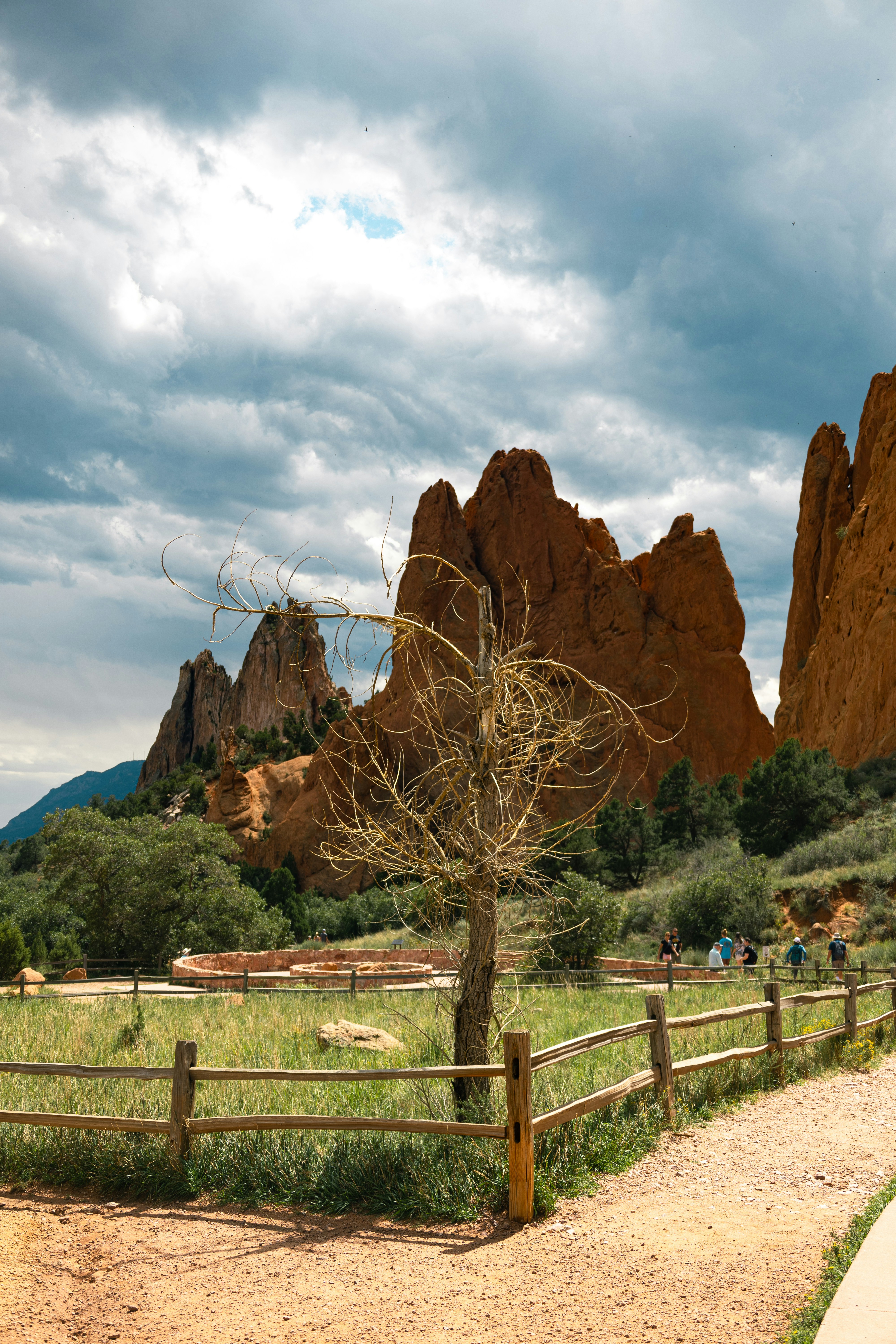 Um caminho de terra que leva a uma área gramada com montanhas ao fundo ...
