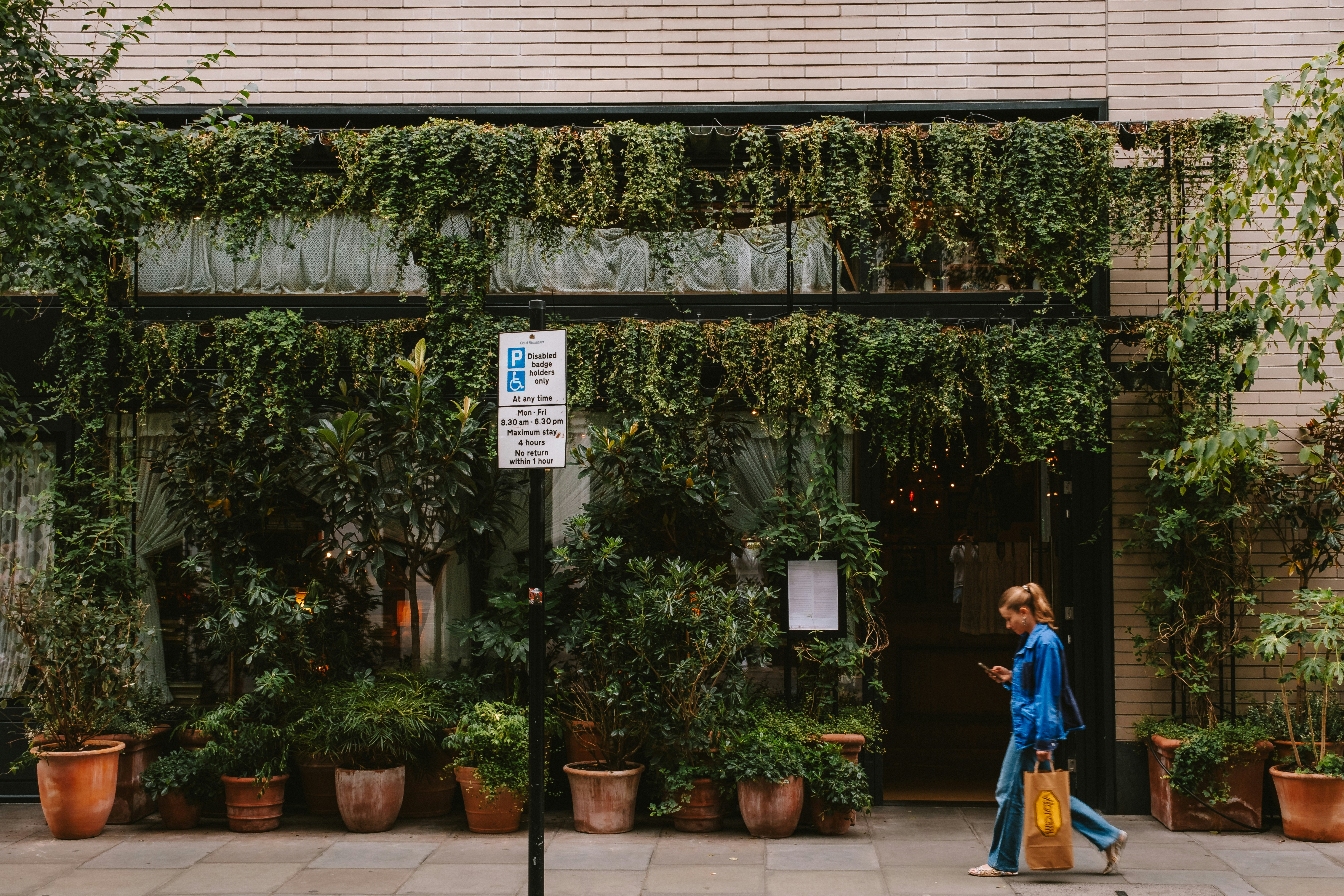 A woman walking down a street past a building photo – Free London Image ...