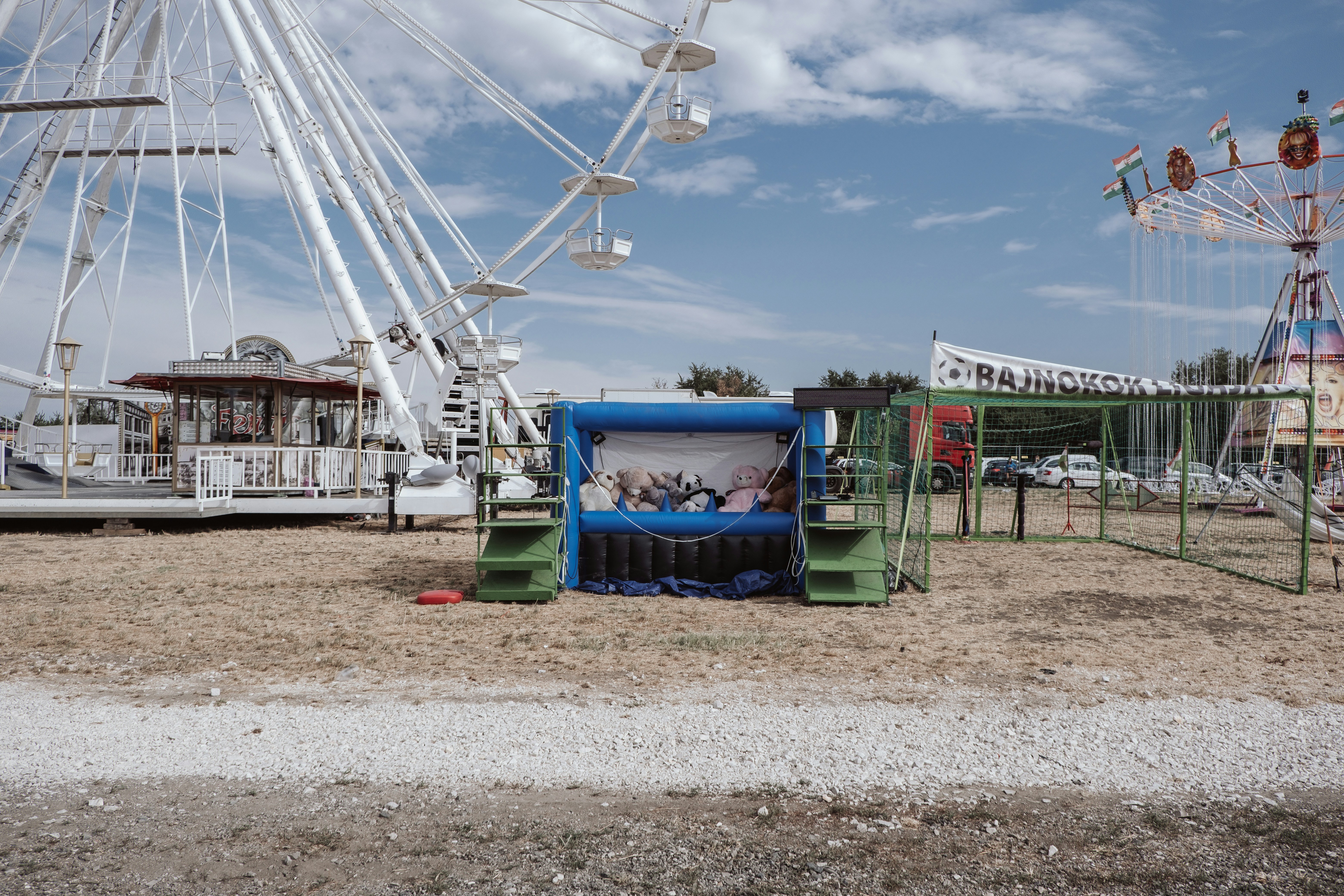 Empty amusement park with a ferris wheel and colorful ride under a blue sky.
