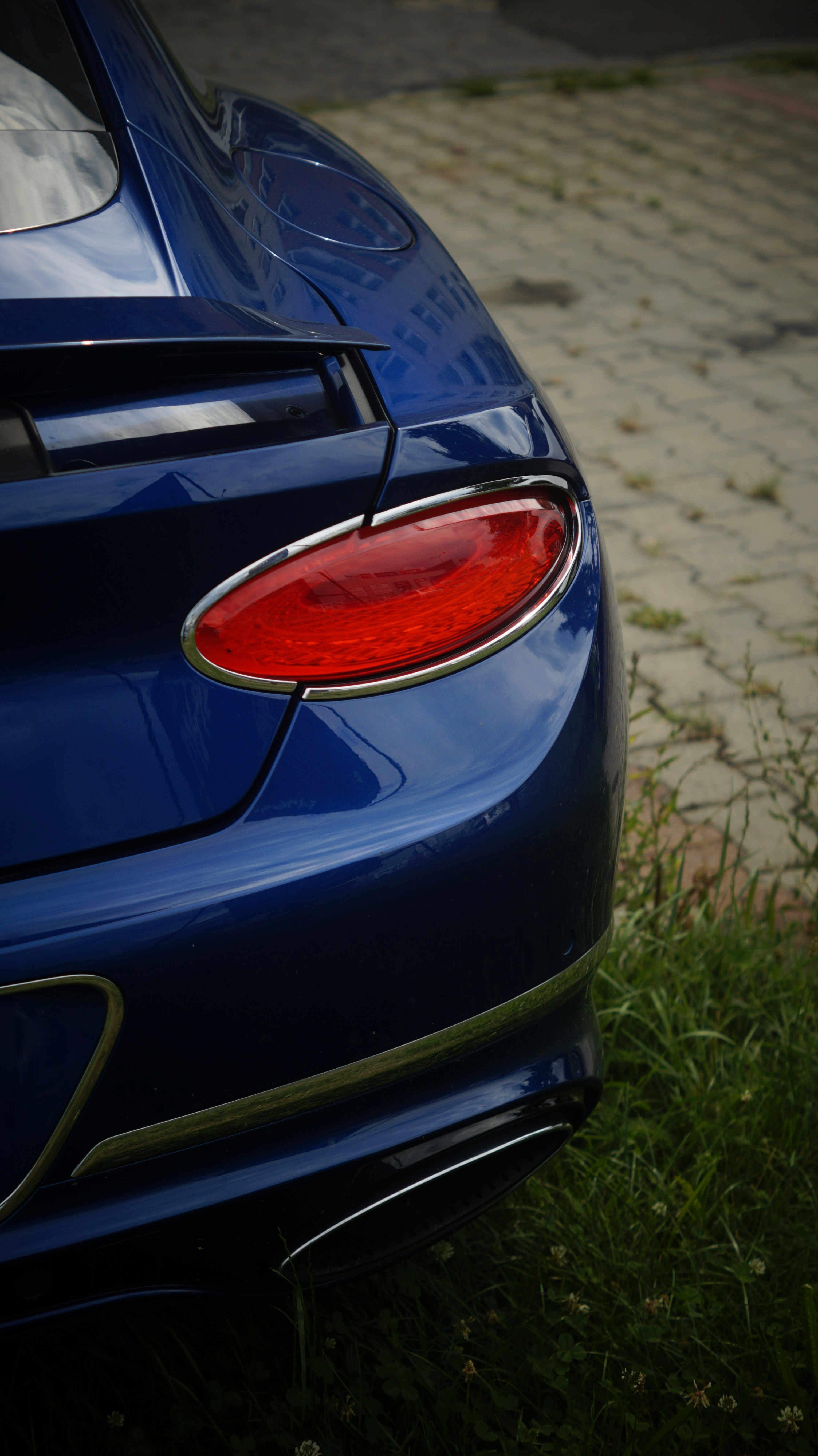 Close-up view of a sleek blue sports car's rear, showcasing its distinctive taillight and aerodynamic curves.