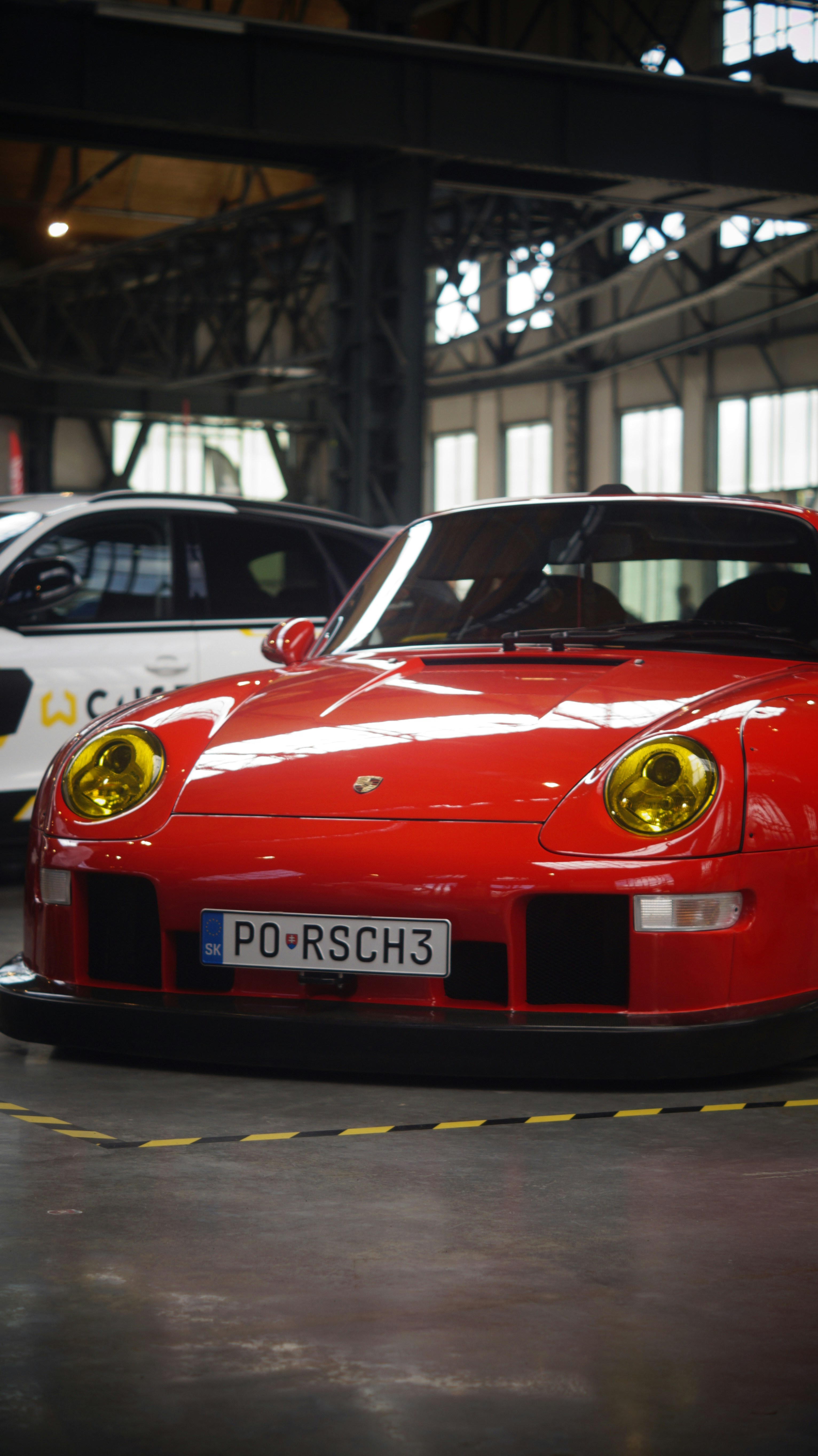 Crimson Porsche 911 at the heart of an iron-and-glass showroom