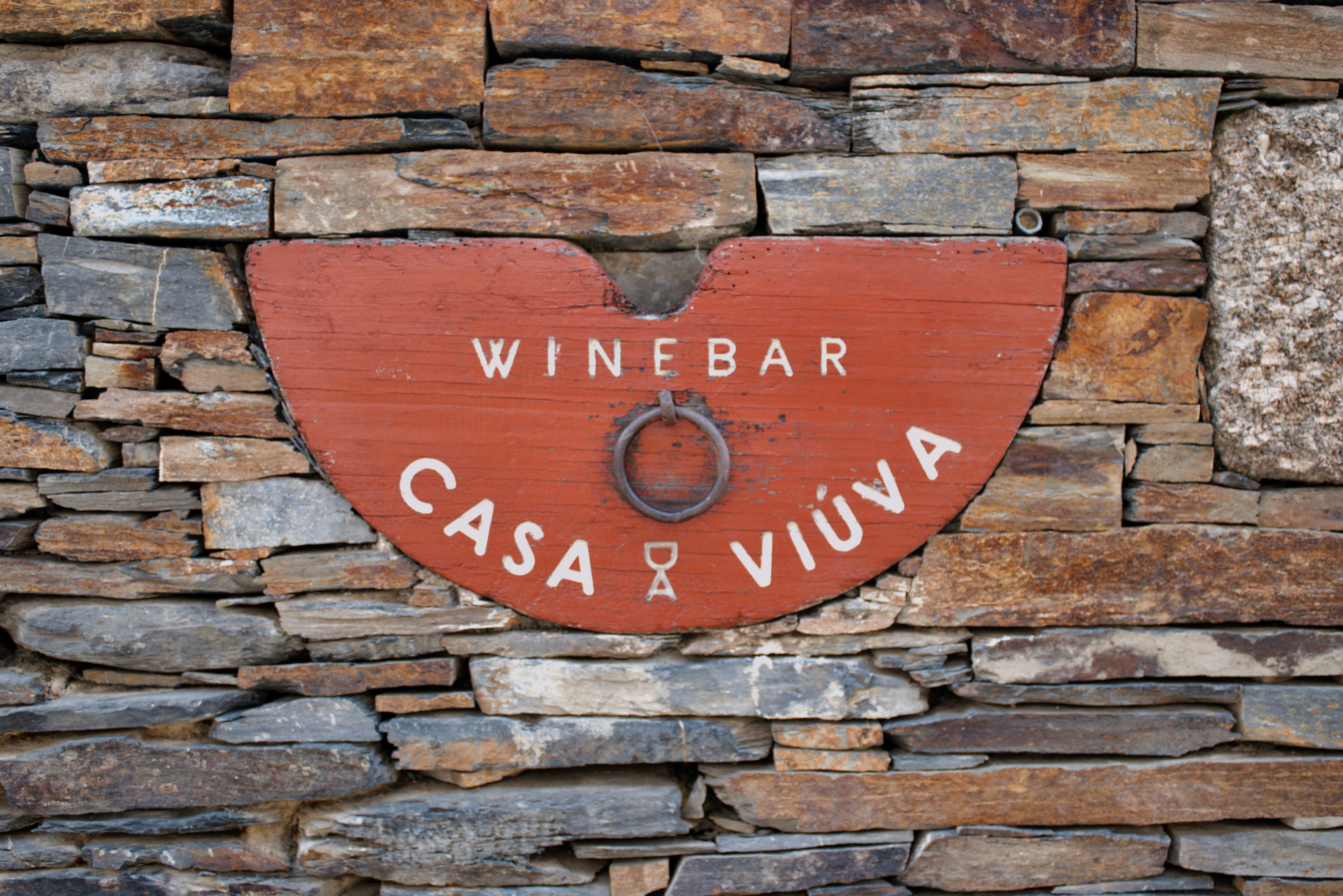 Red Semicircular Wine Bar Sign Anchored in Weathered Stone Wall