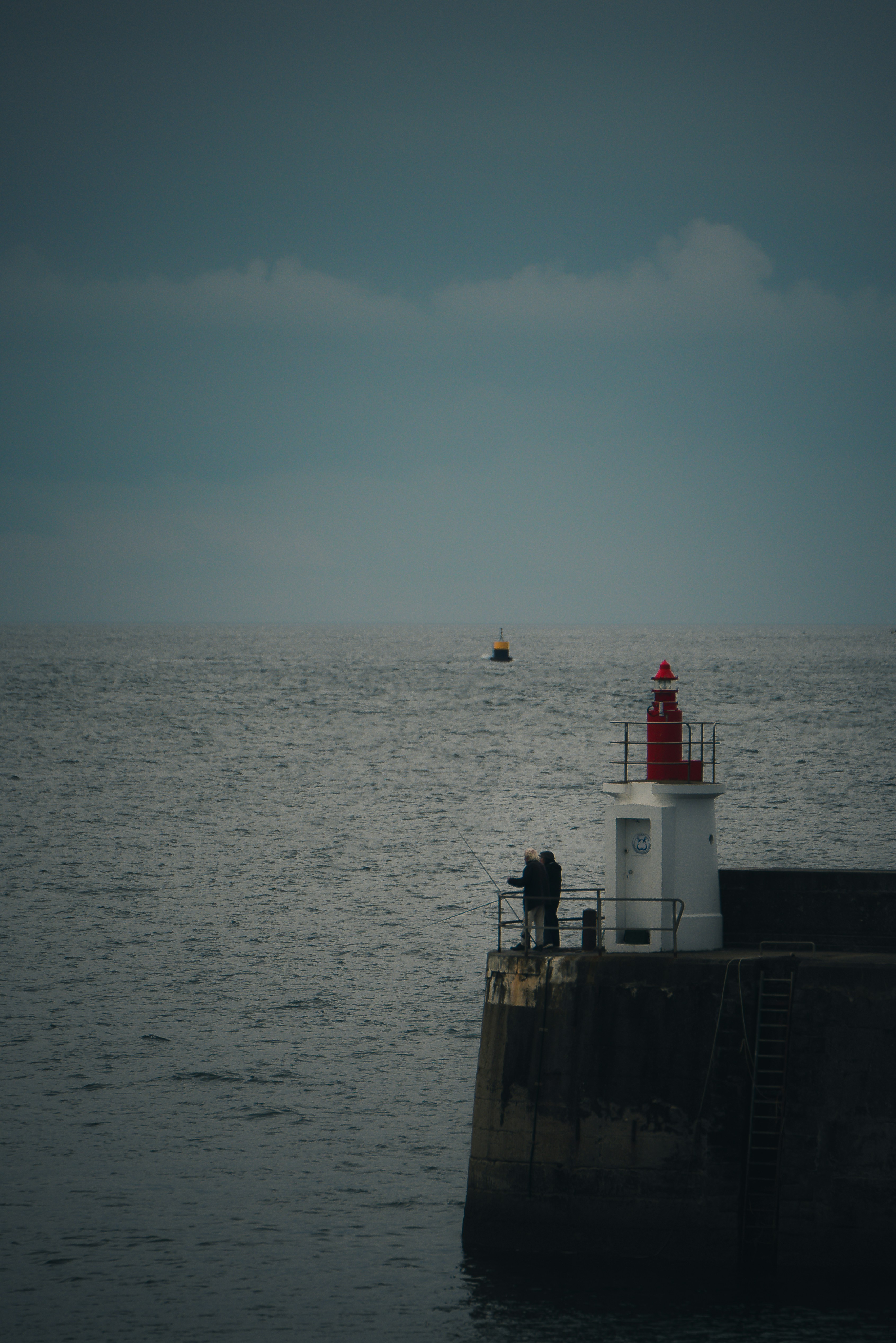 A lighthouse sitting on top of a pier next to the ocean photo – Free ...