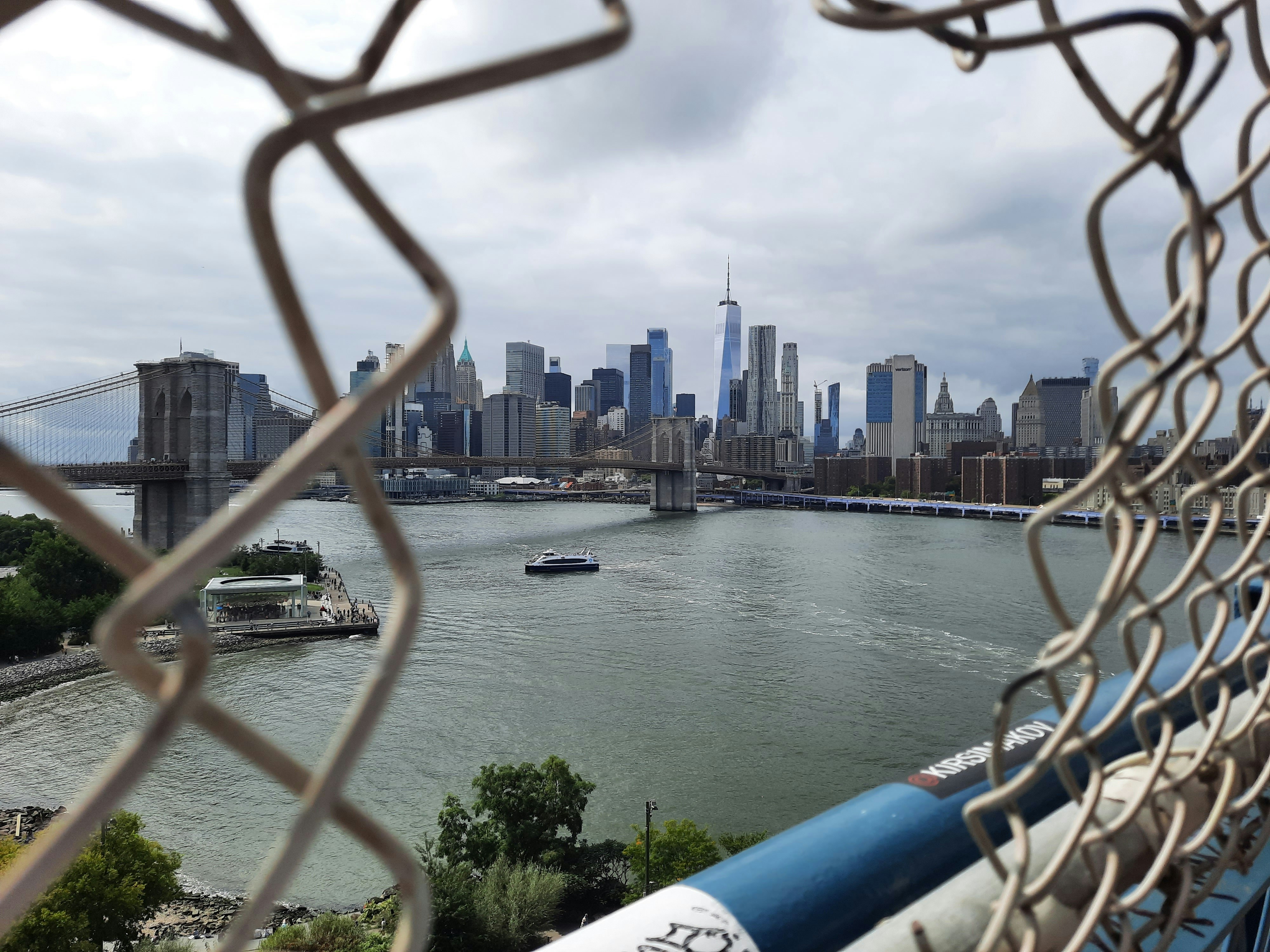 Fence-Framed Skyline: Riverfront Moment in Steel and Glass