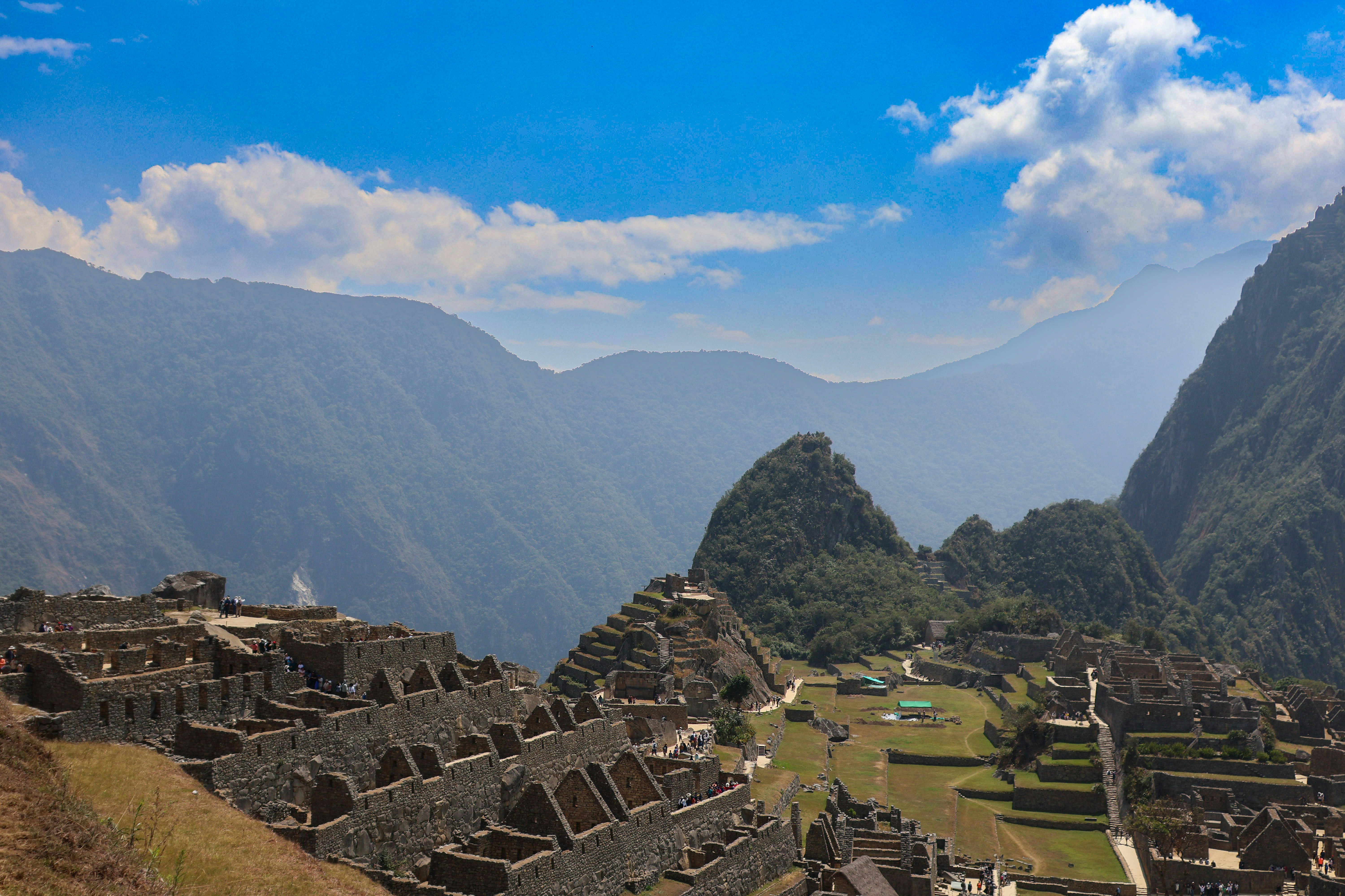 Machu Picchu ruins nestled in the Andes under a vibrant blue sky with scattered clouds.