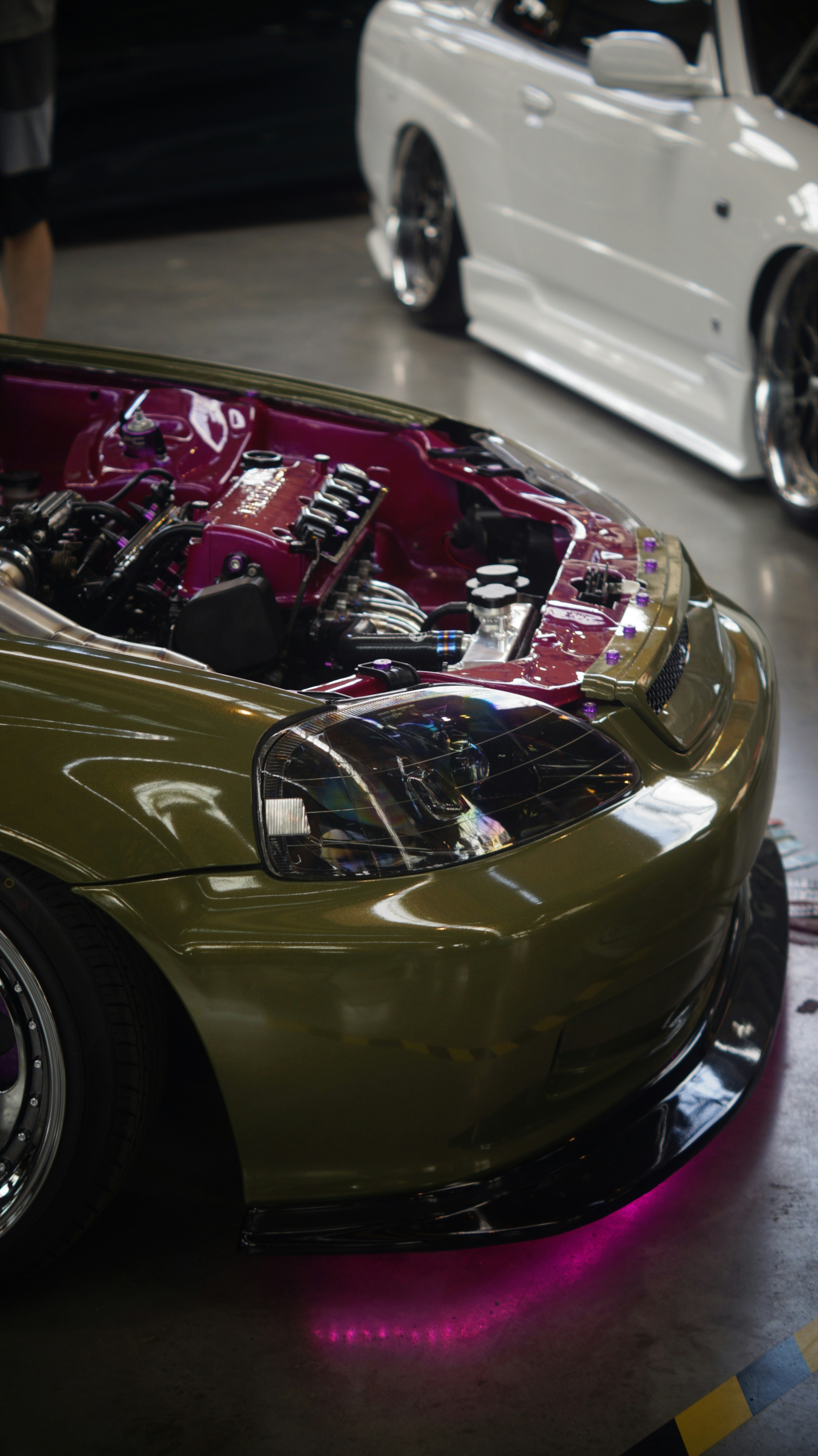 A green sports car parked next to a white car