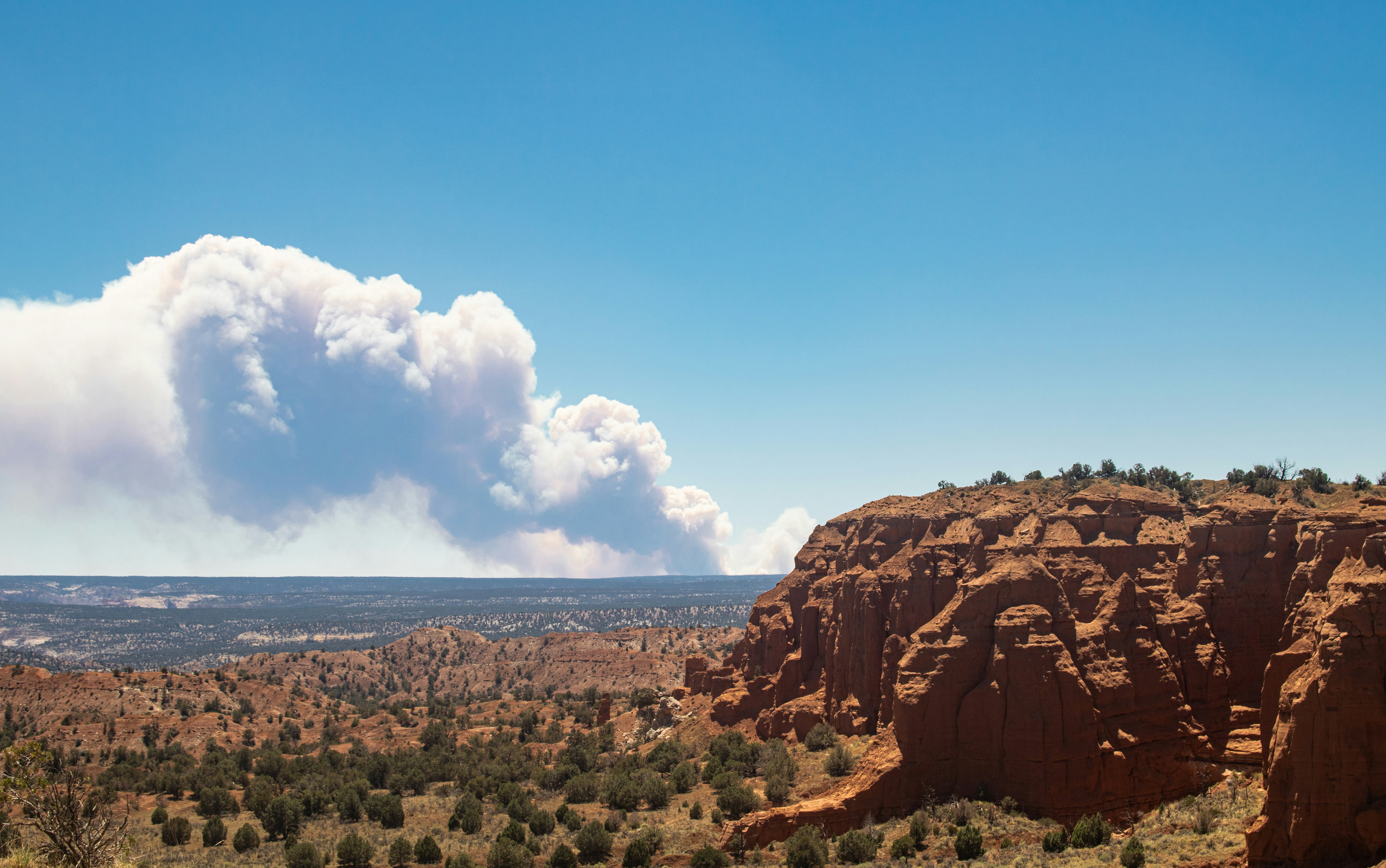 Crimson Cliff Over a Desert Expanse Under a Cloud-Puffed Sky