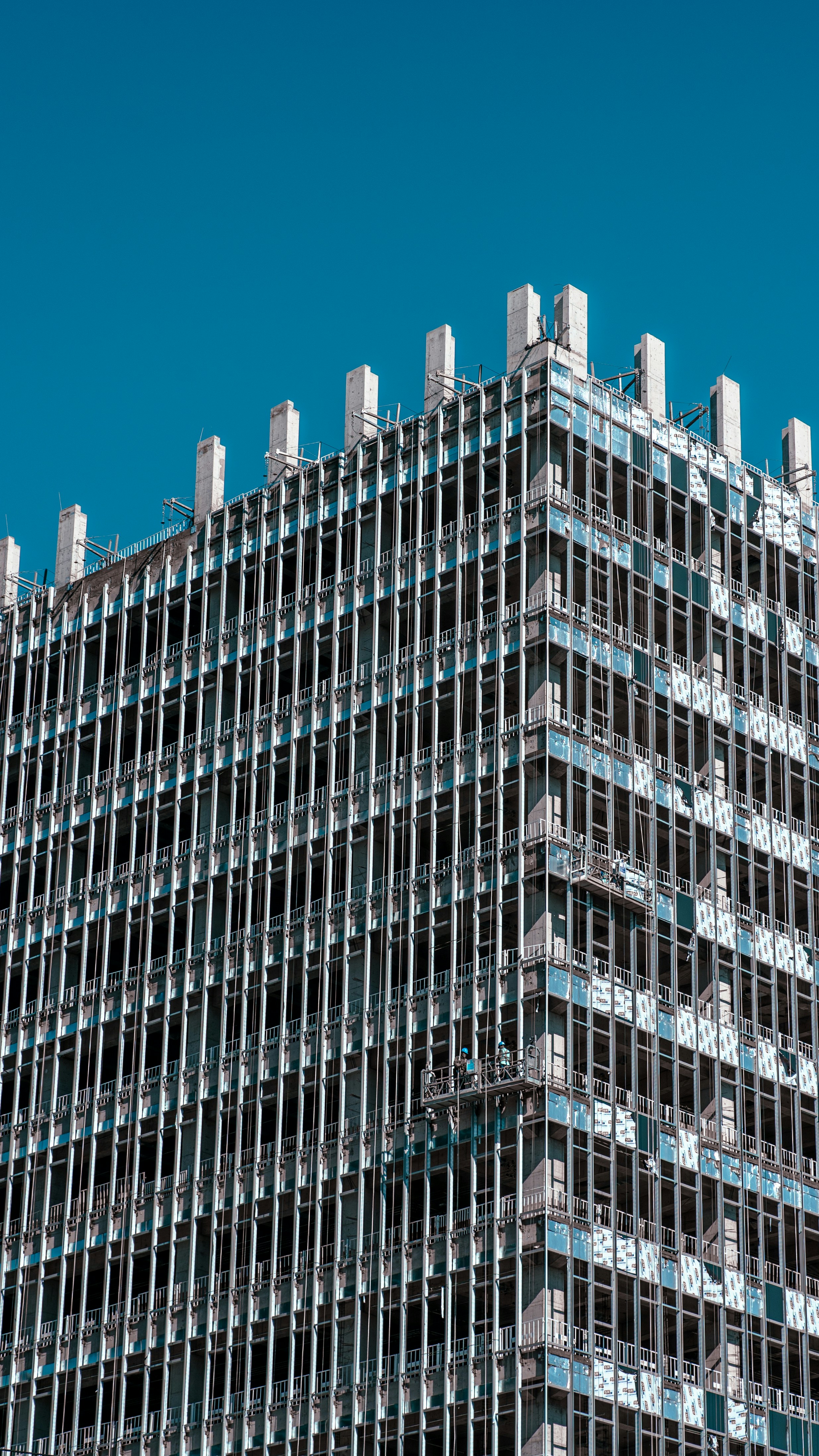 Skyward Skeleton: A Grid of Concrete Spires Against a Pristine Blue