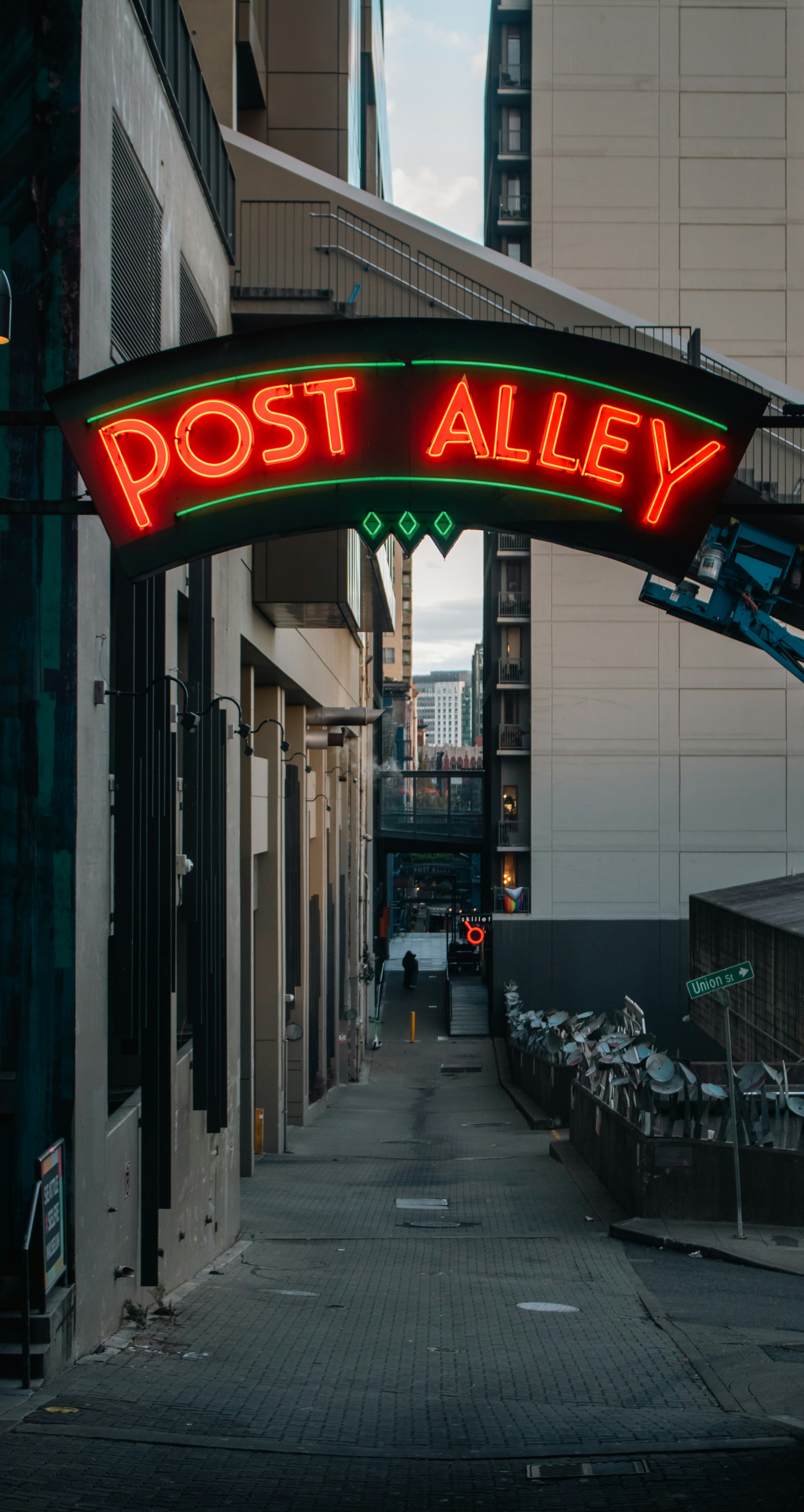 A neon sign that reads post alley on the side of a building photo ...