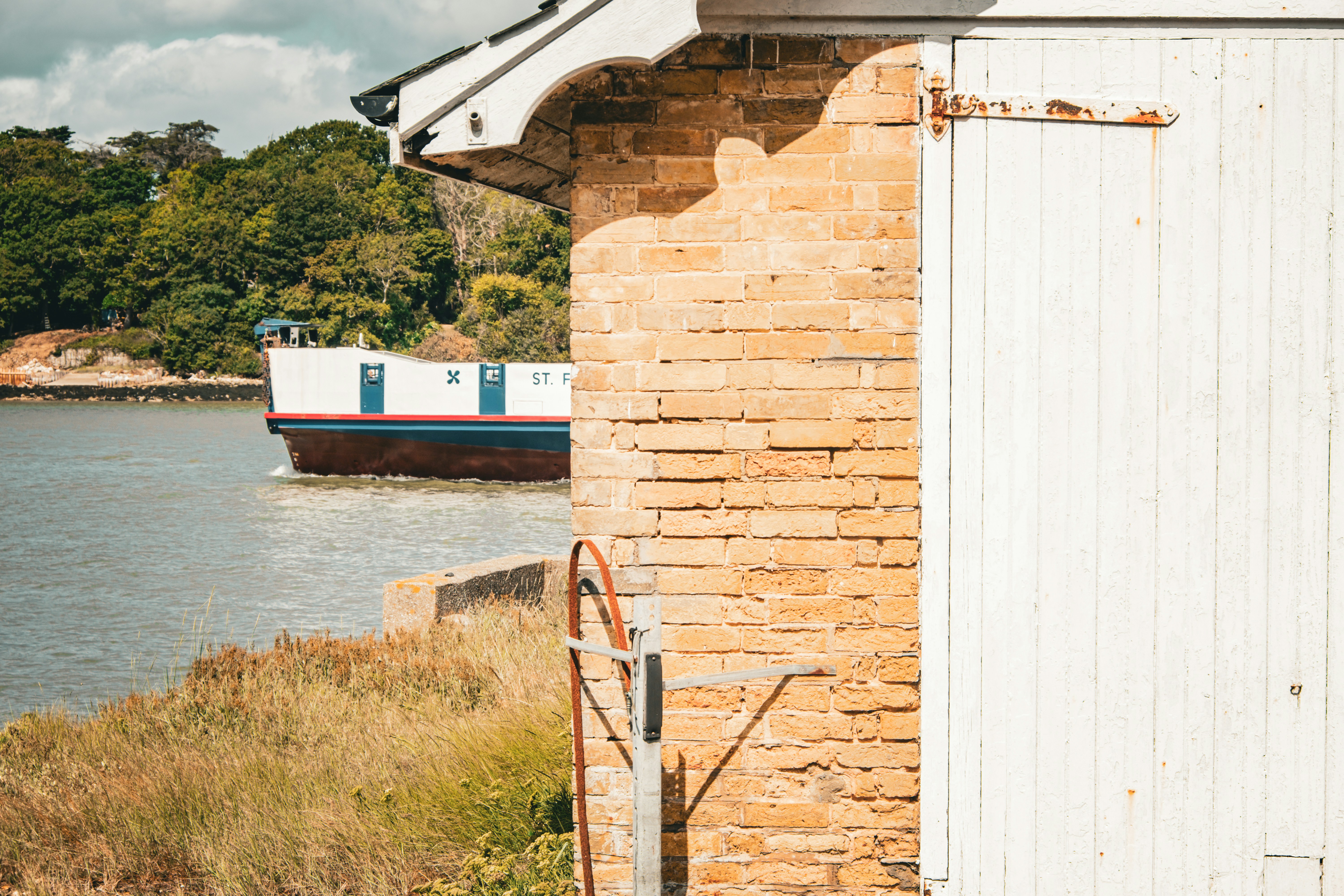 A brick building with a boat in the water behind it photo – Free ...