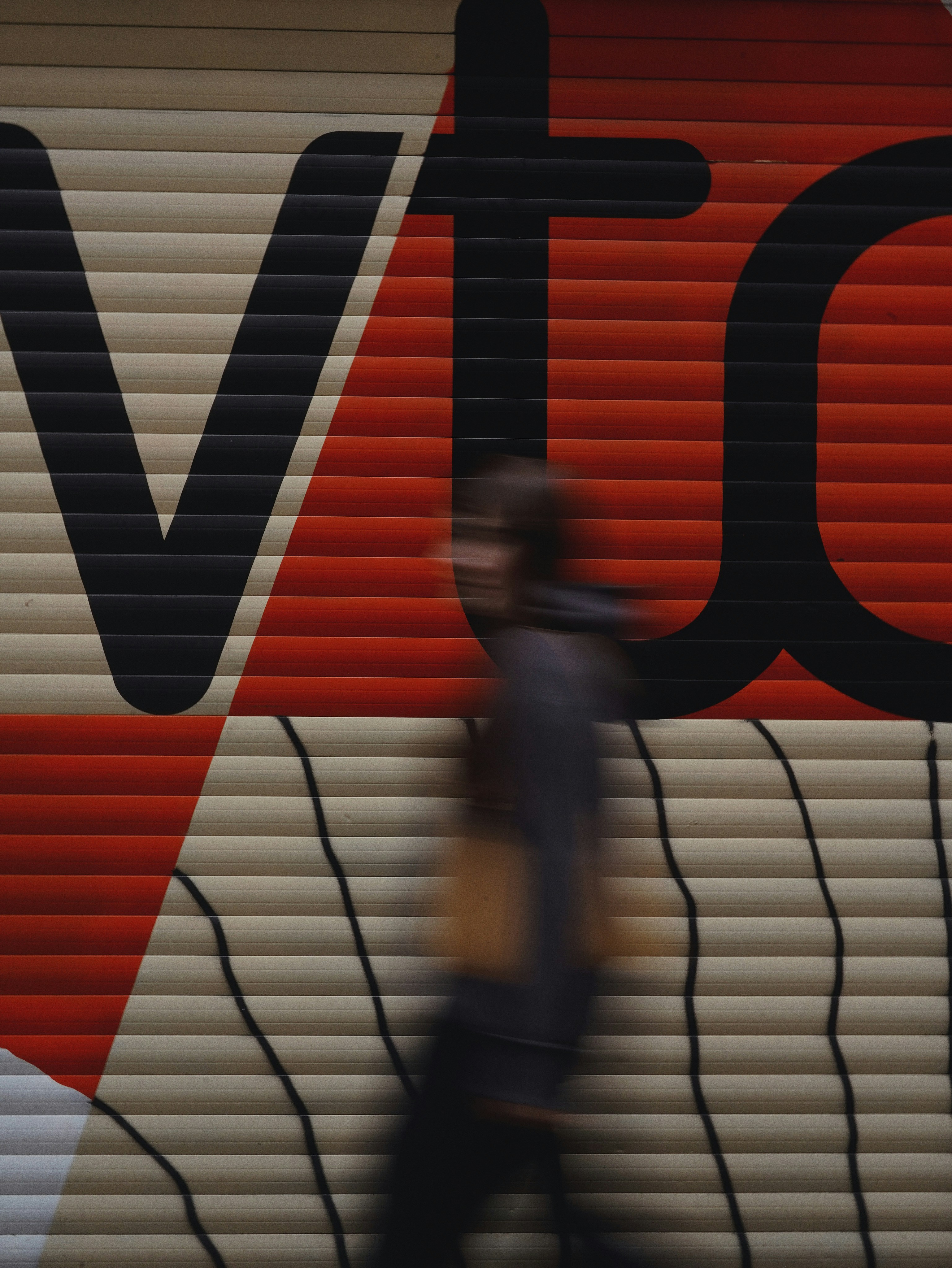A blurry photo of a man walking in front of a wall