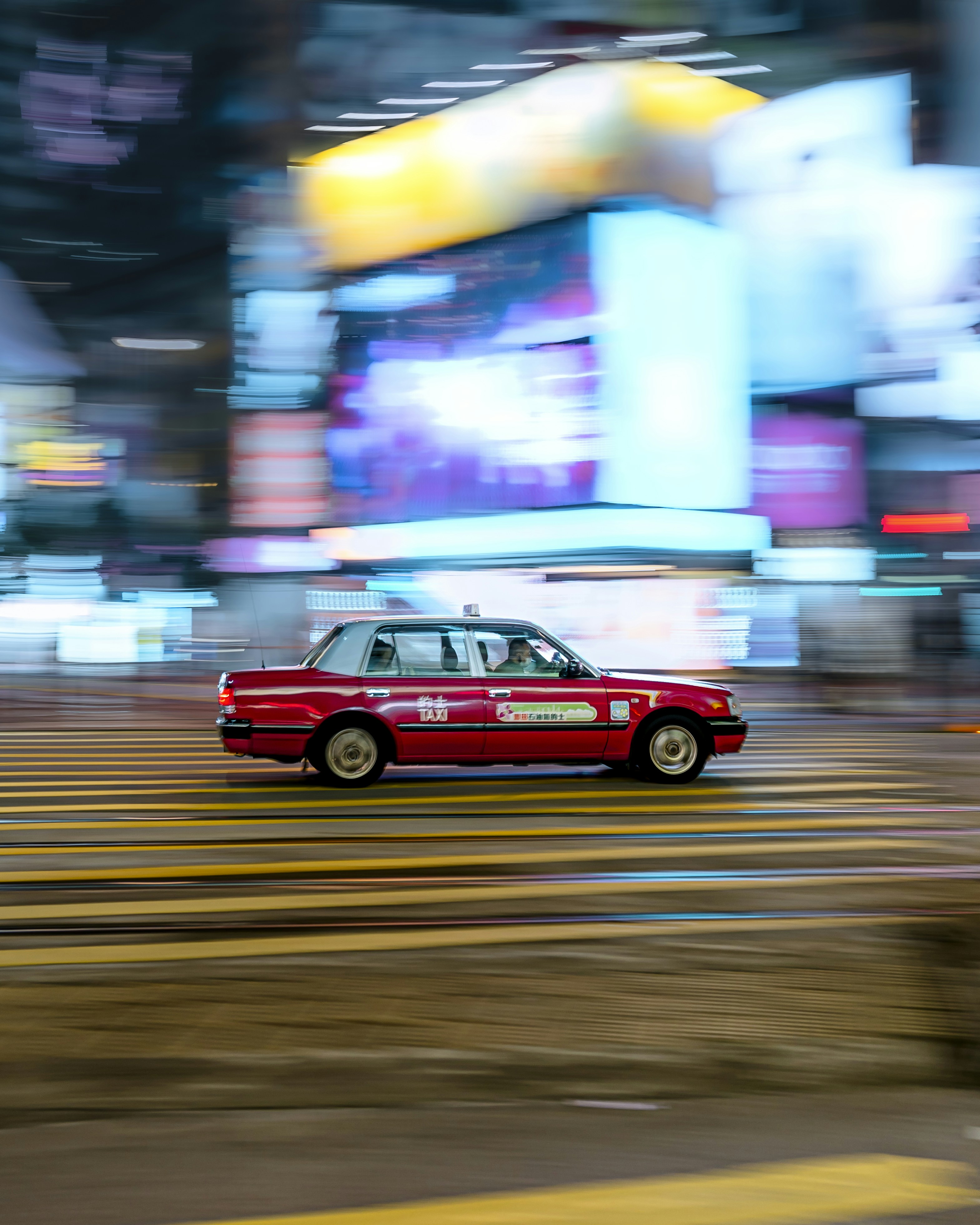 A red taxi cab driving down a street next to tall buildings photo ...