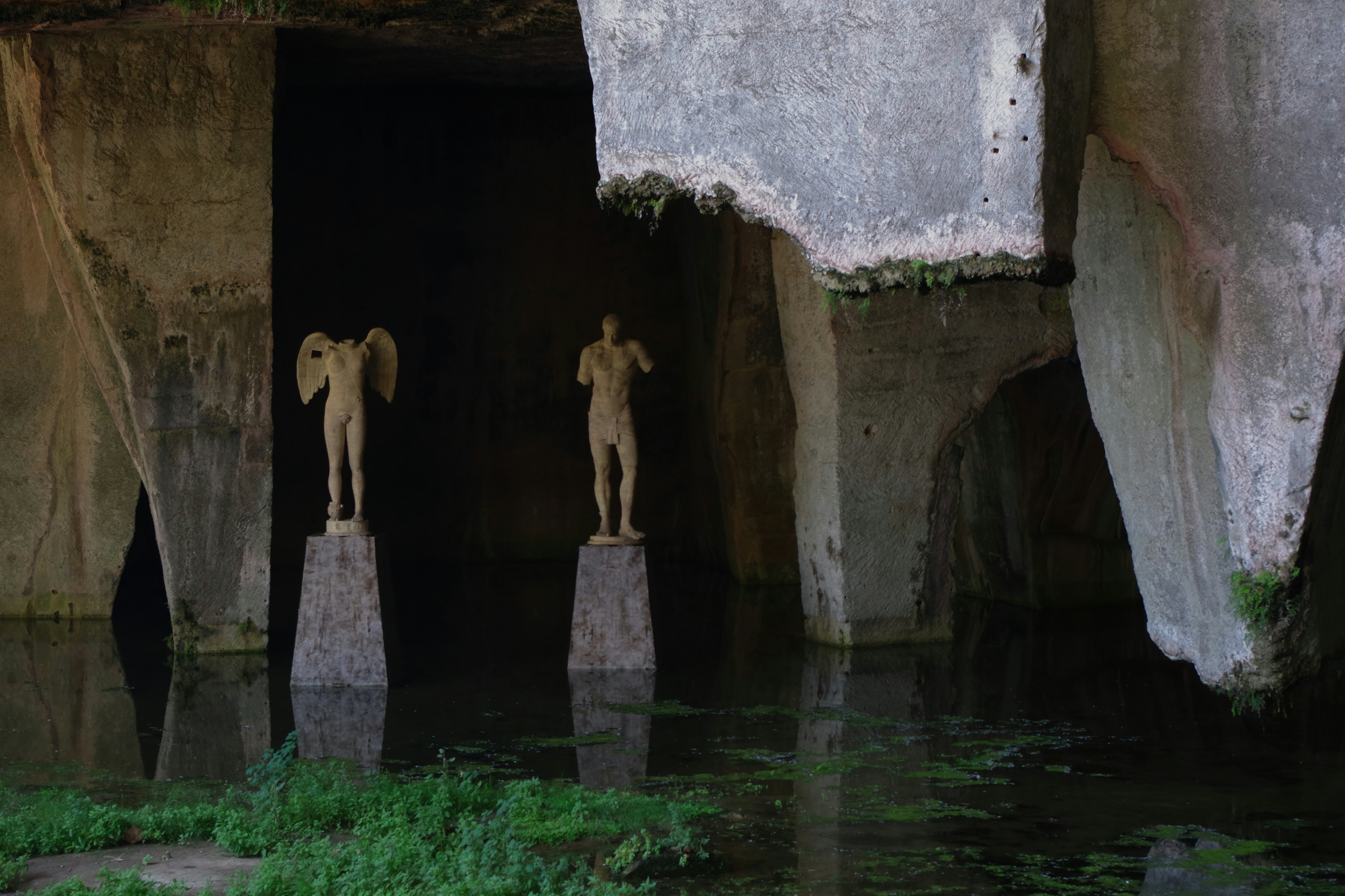 A group of statues in a cave next to a body of water photo – Free ...