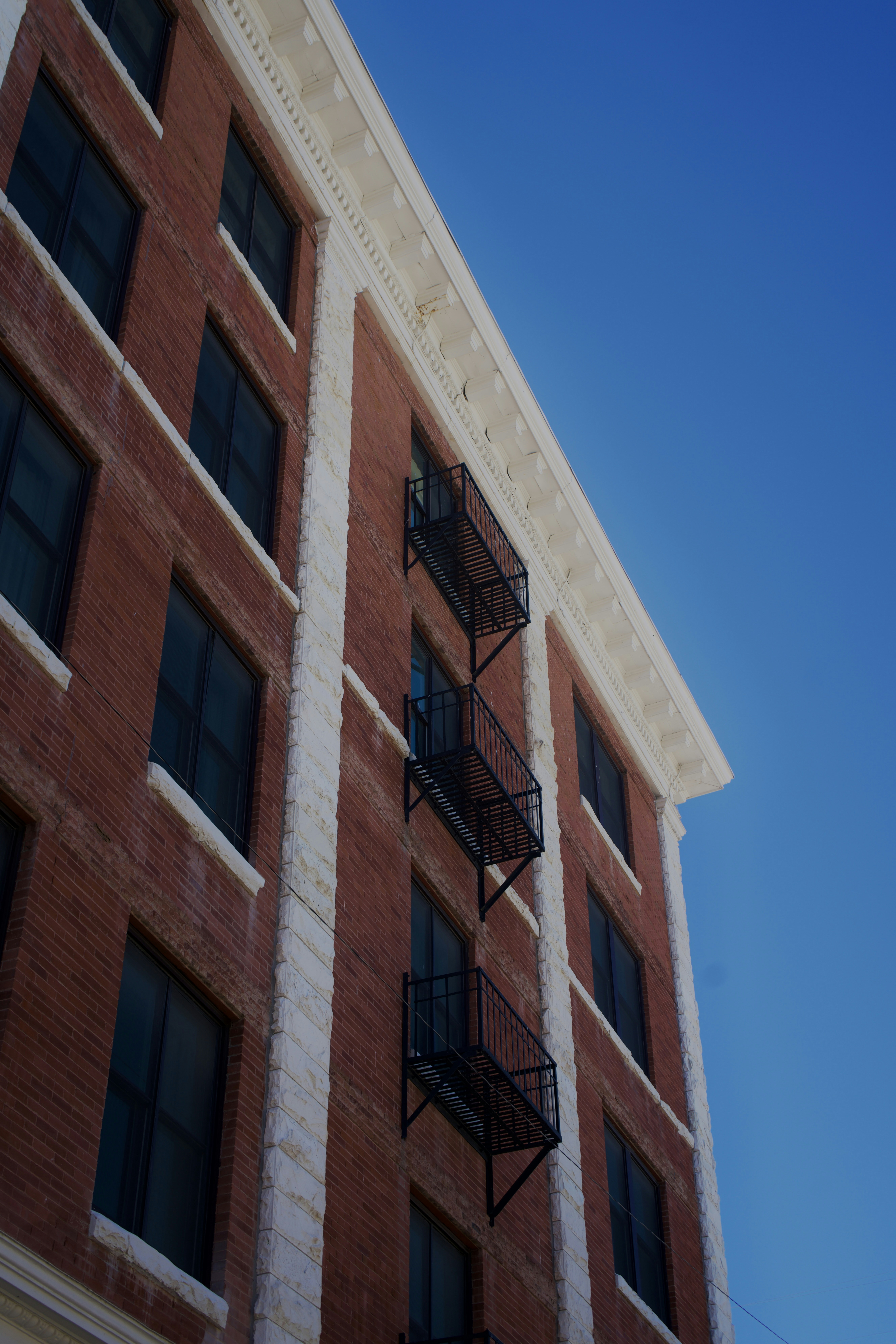 A tall brick building with a fire escape photo – Free Building Image on ...