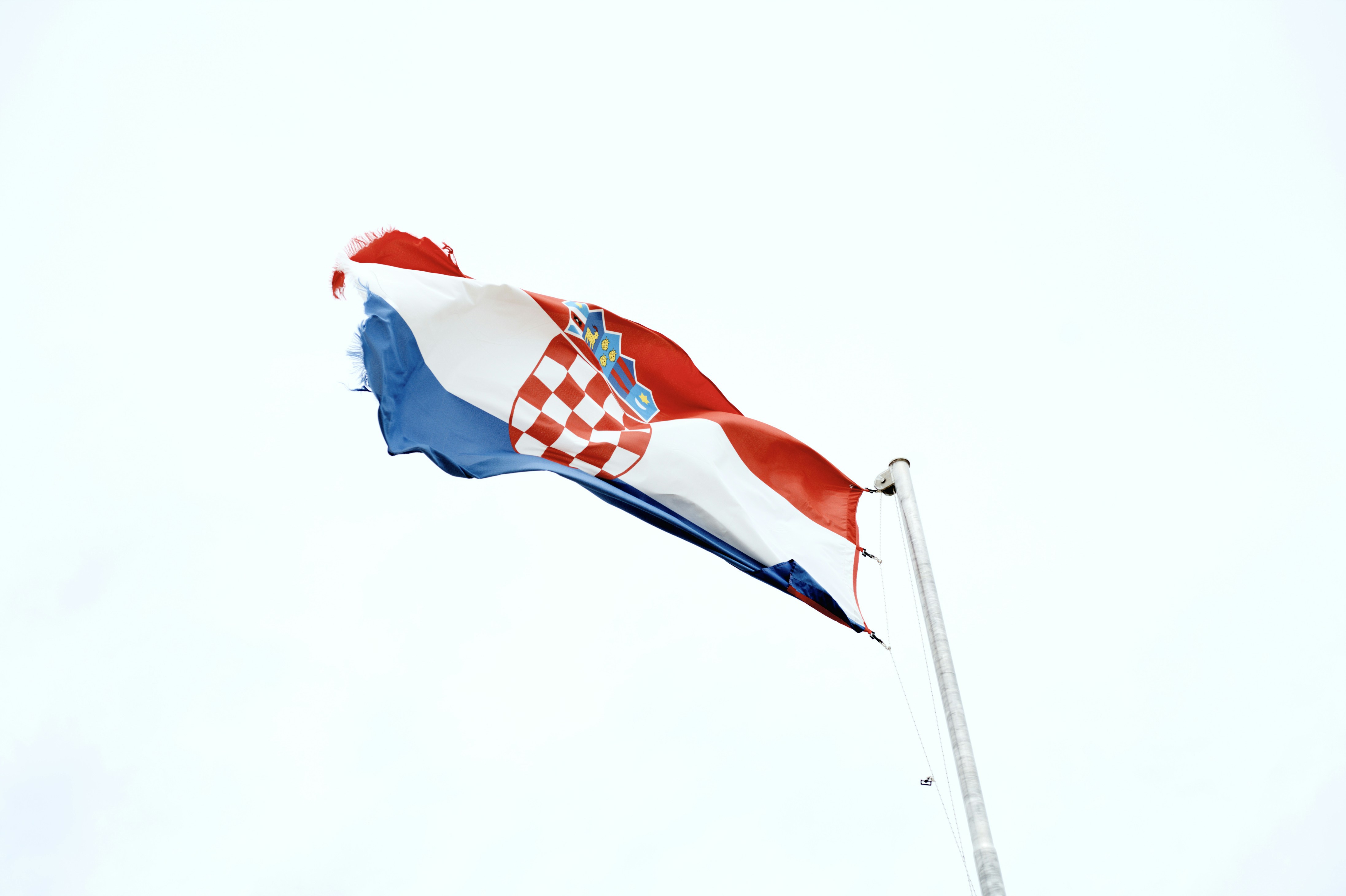 Croatian Flag Ripples Along a Slender Pole Against a Bleached Sky