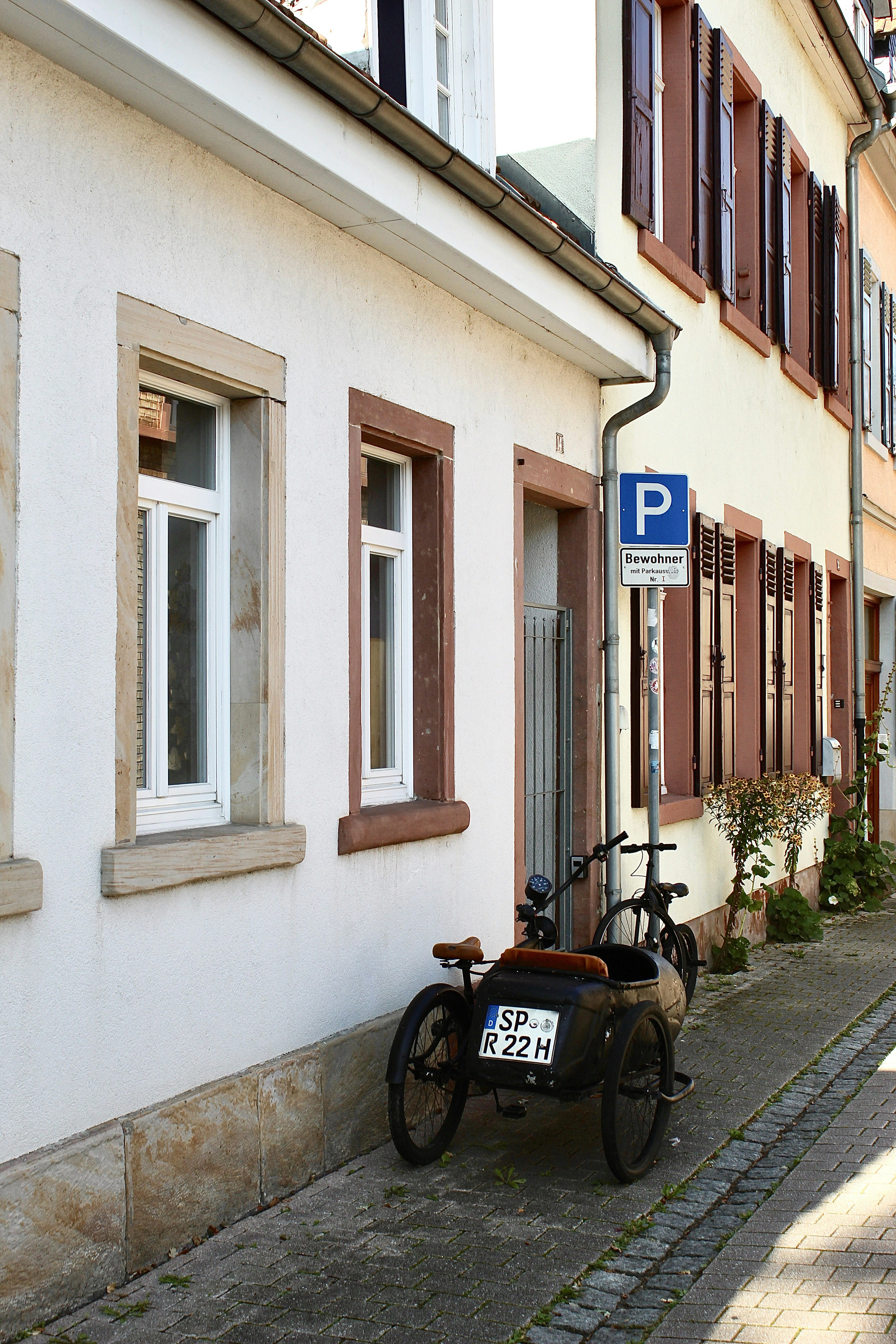 Sunlit Lane: a vintage cargo trike rests beside a pastel European townhouse