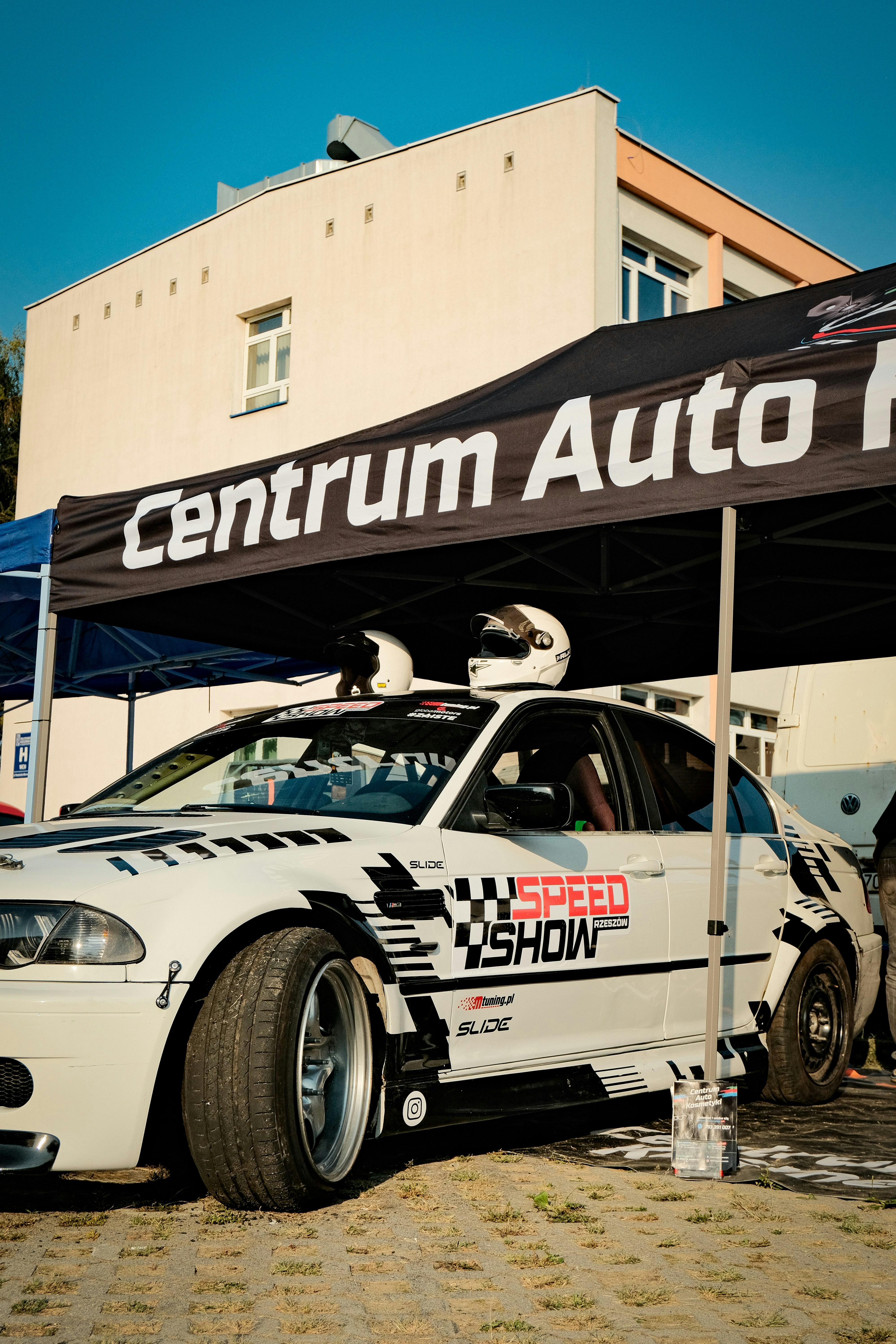 A white car parked under a black and white awning