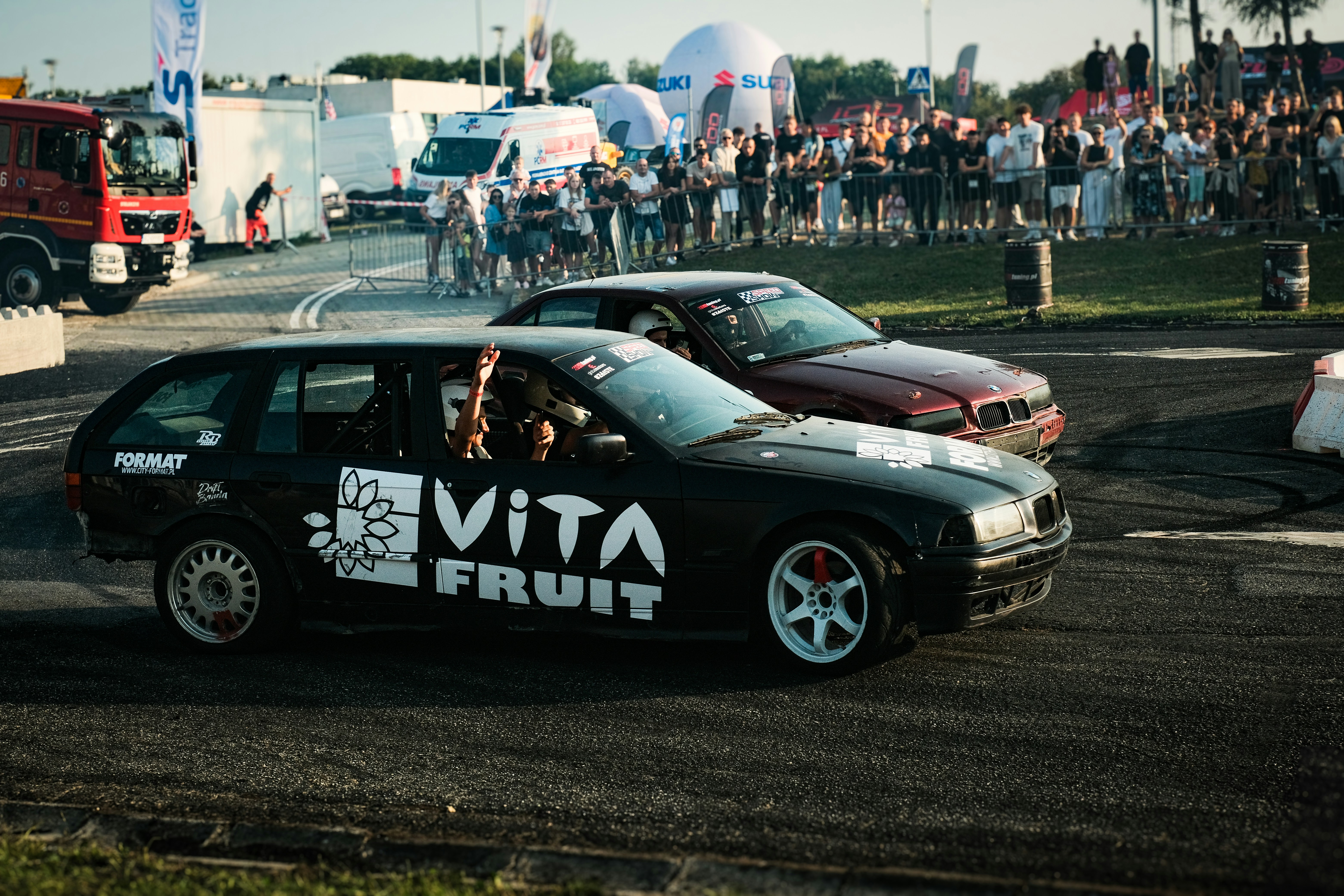 Vita Fruity Drift: A black wagon with bold white branding powers through the crowd