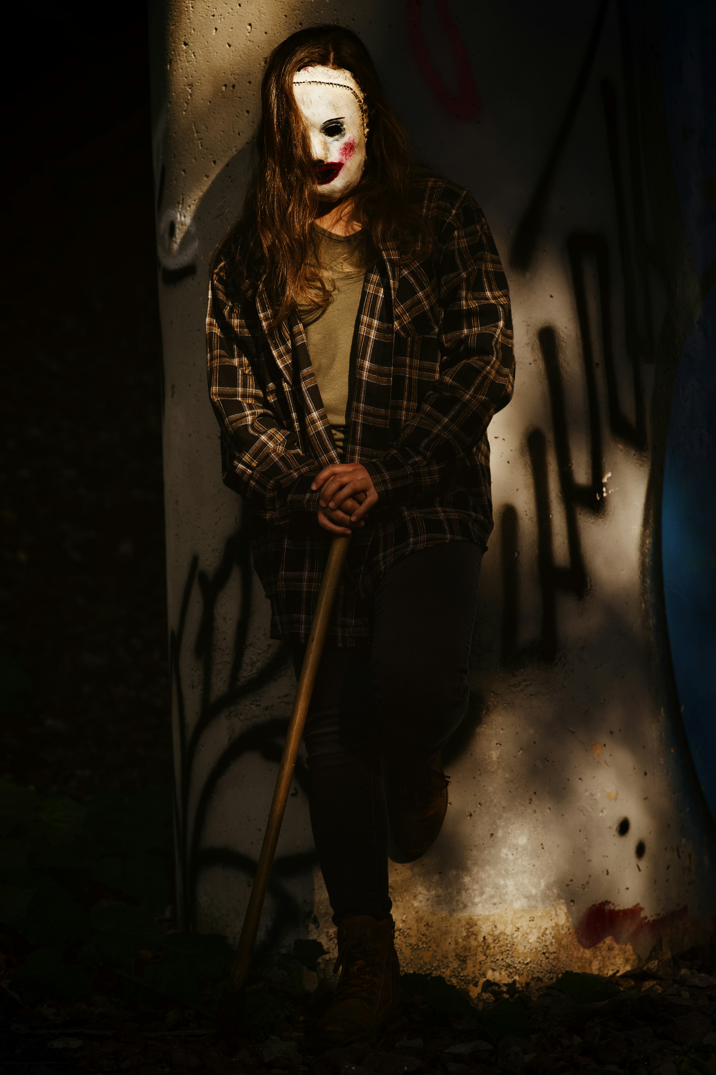 A person with a mask and a cane standing in front of a wall photo ...