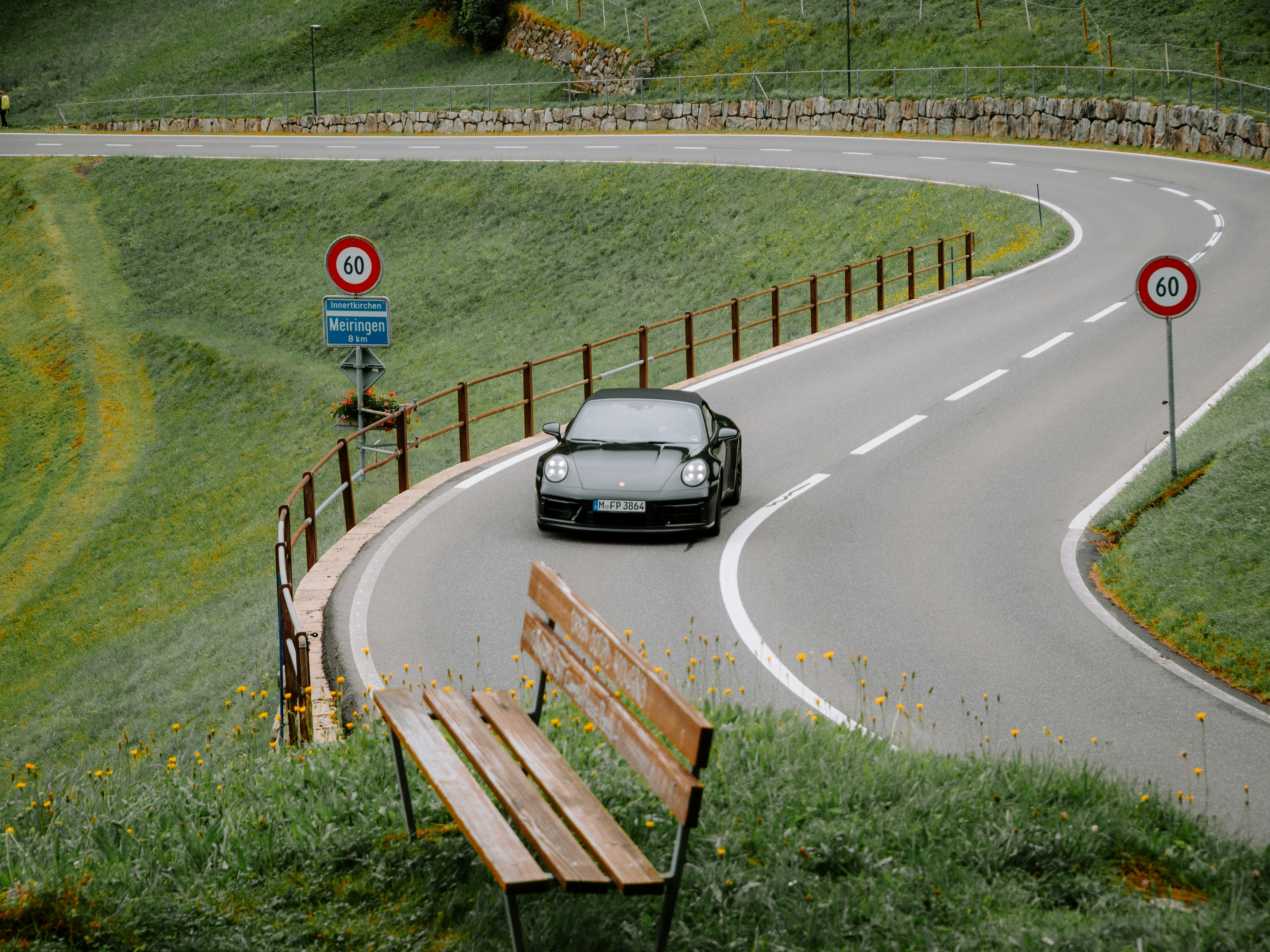 Sinuous Roadside Ascent: A Compact Convertible Navigates a Winding Alpine Path