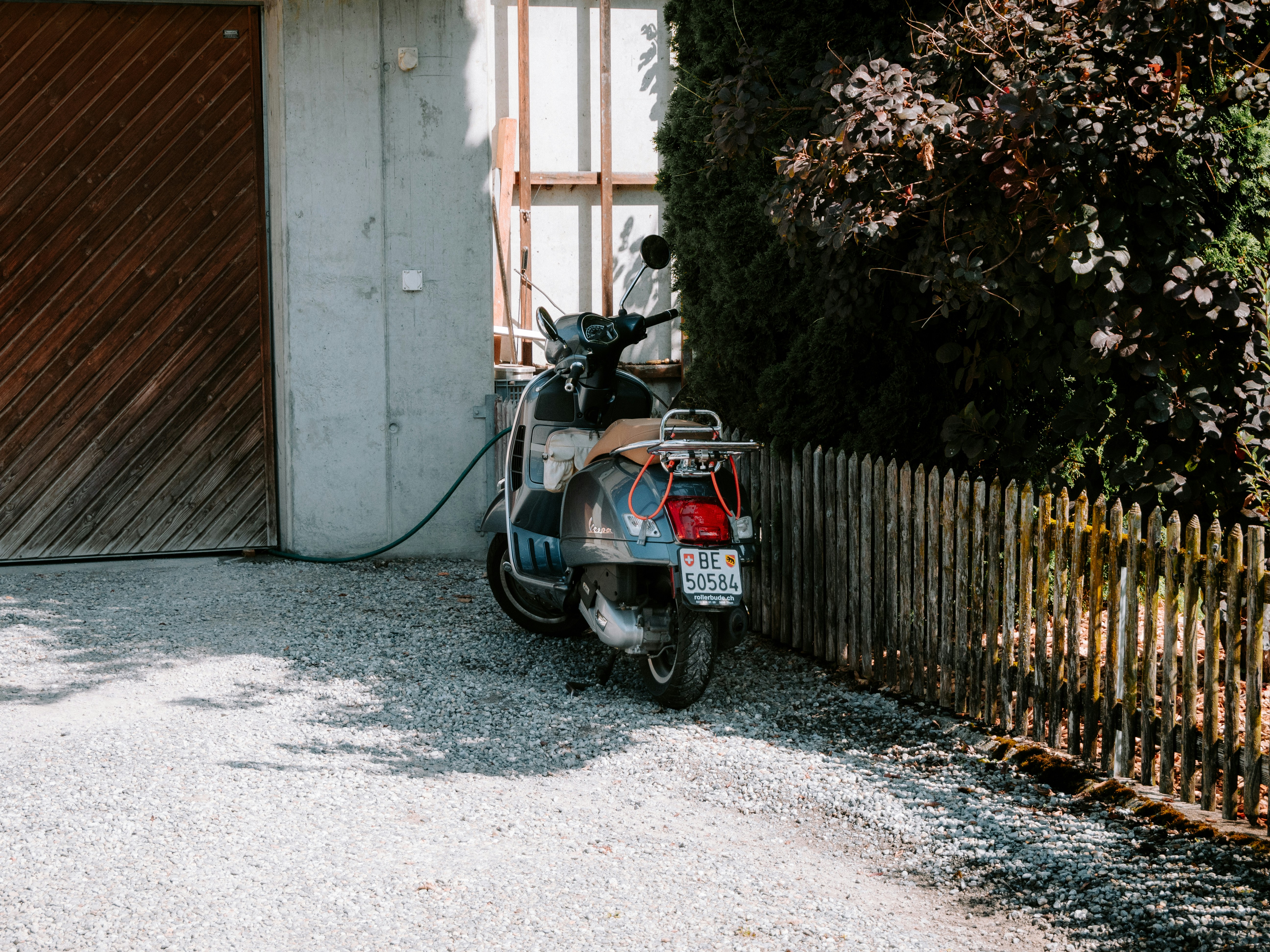 Scooter in the Gravel Courtyard: Daylight Between Door and Fence