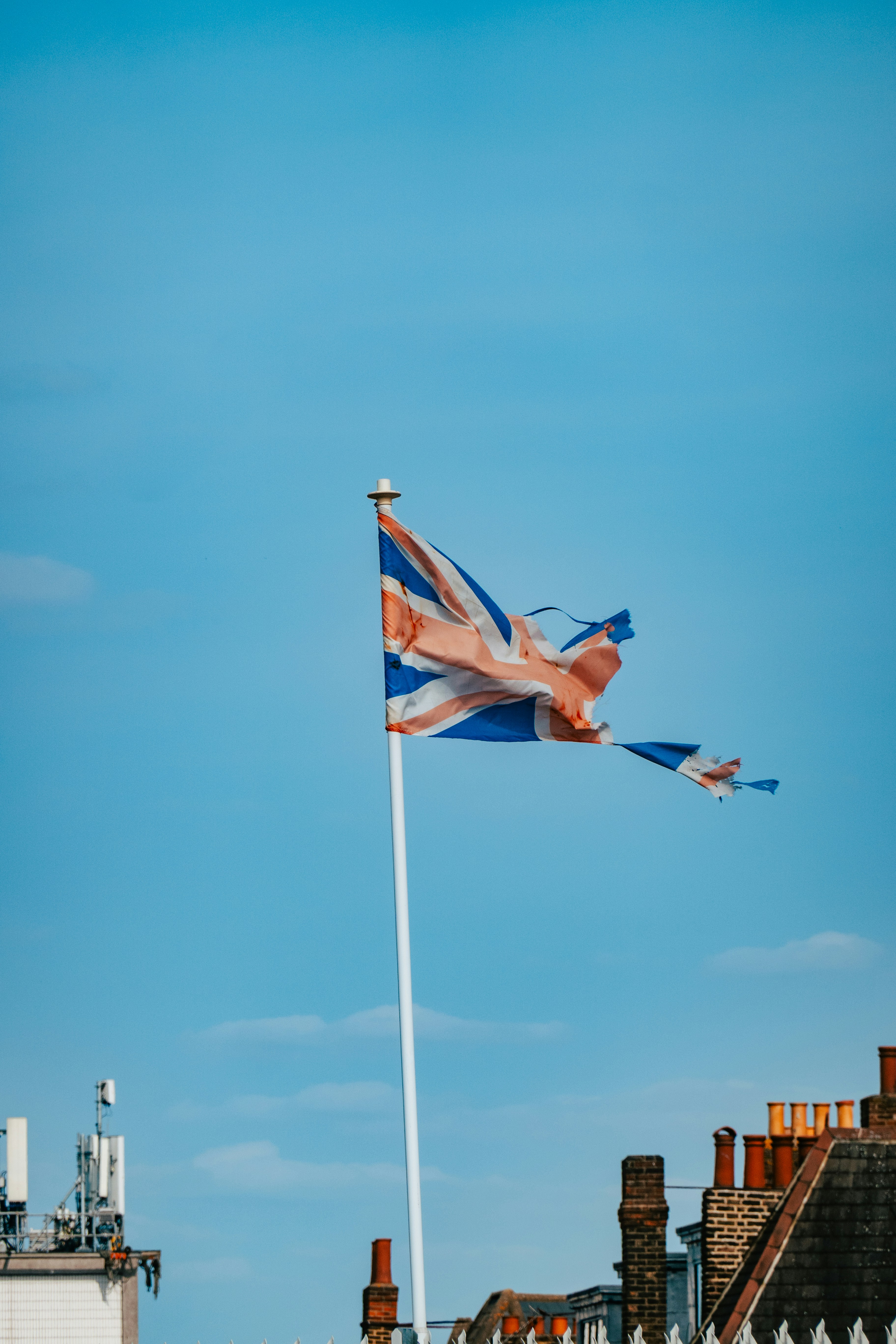 Union Jack in a Brisk Breeze: Flagpole Above a Brick Rooftop Line