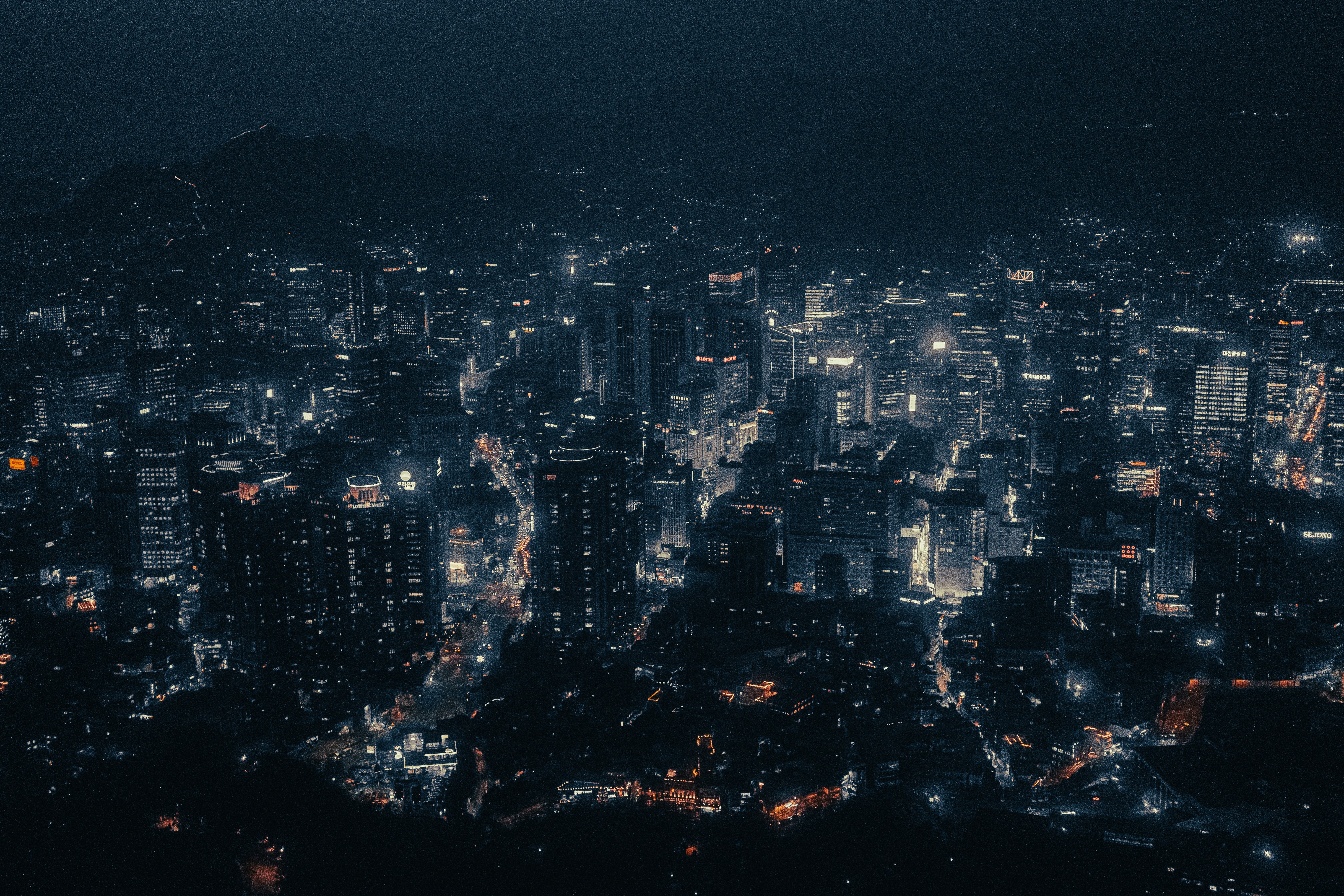 Vibrant city skyline illuminated by countless lights, showcasing a mix of modern architecture and urban life at night.