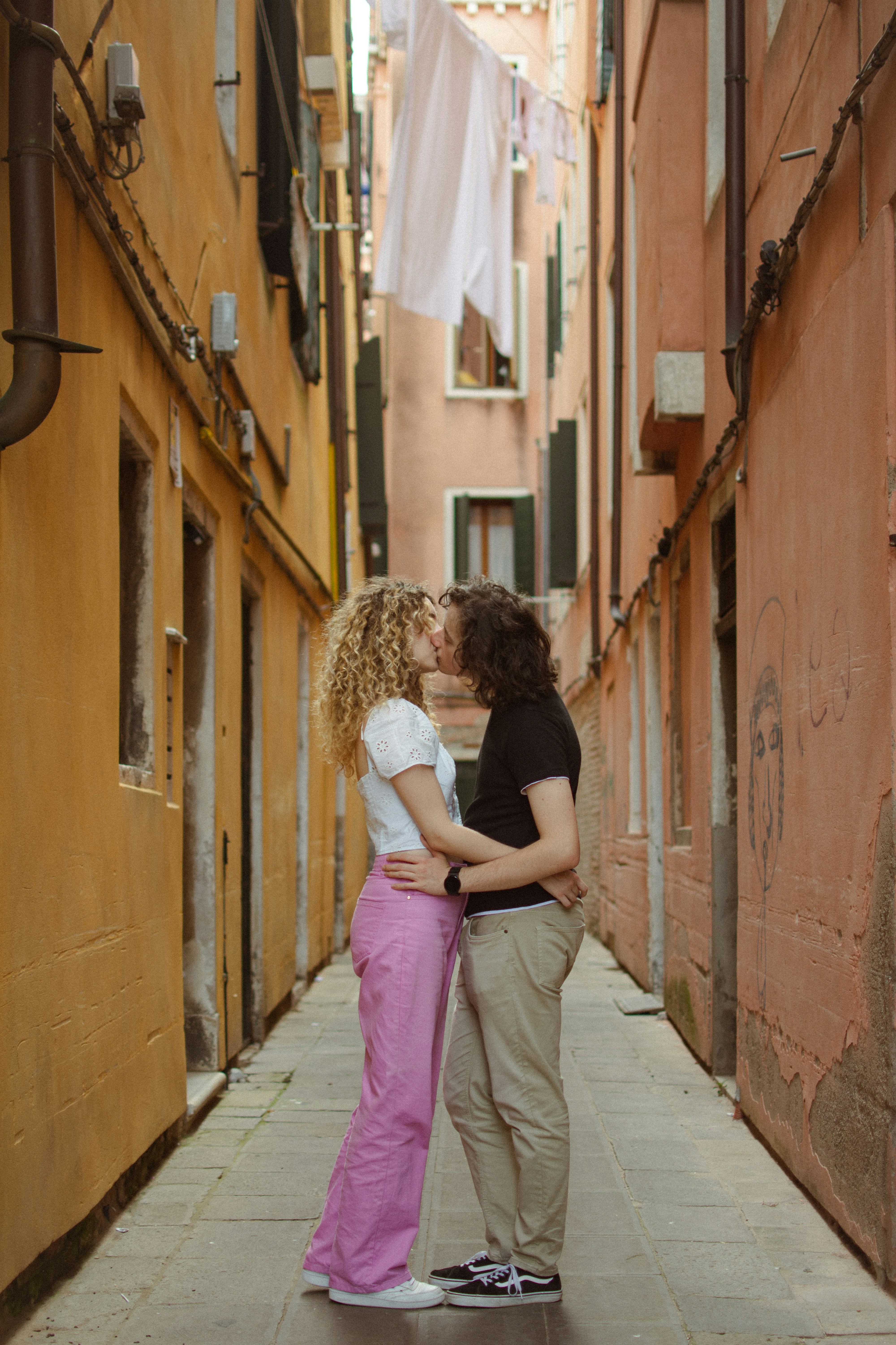 Sunlit Alley Embrace: A Tender Kiss Between Peach-Walled Corridors