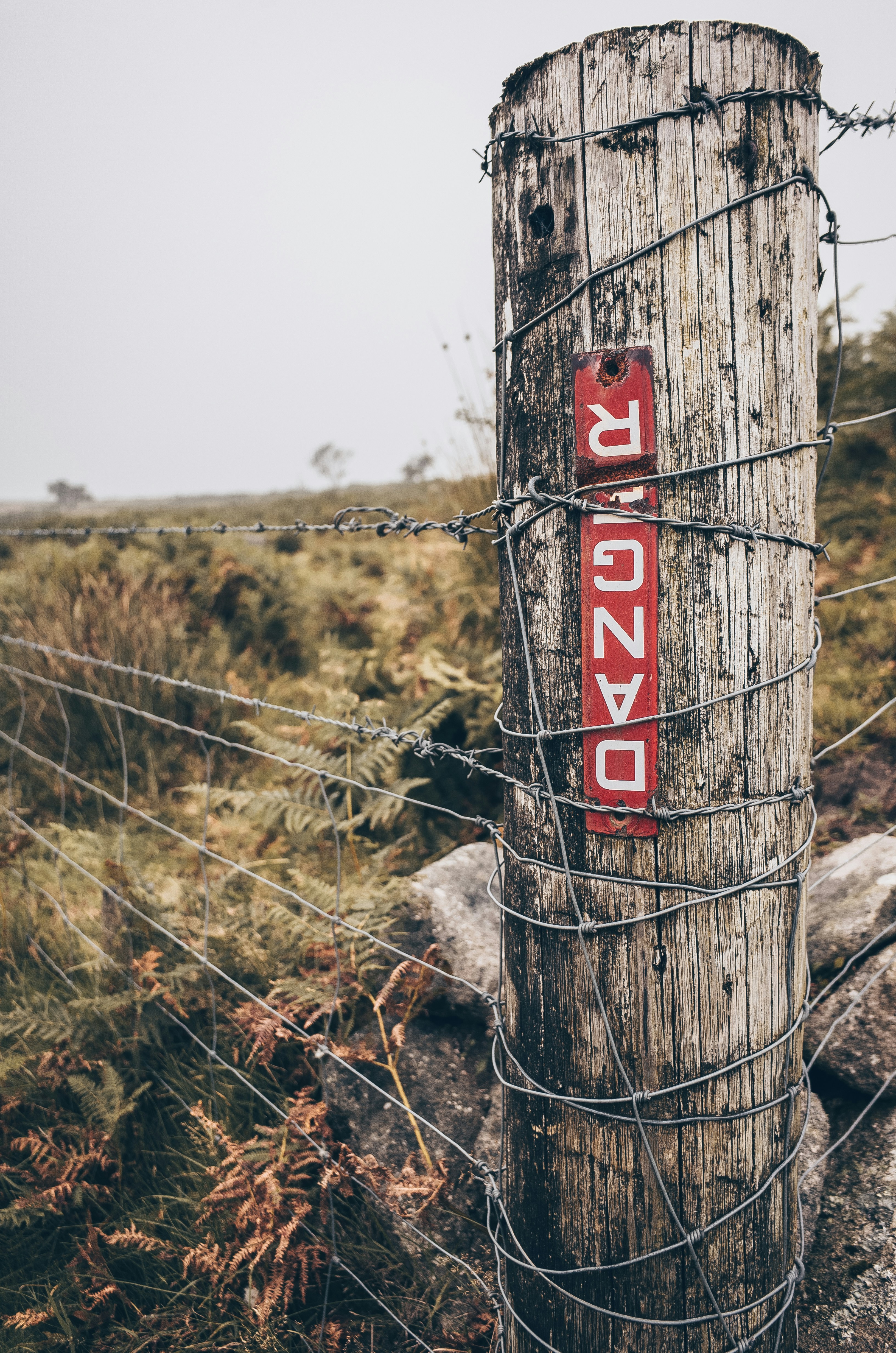 Turn danger on its head. A reused electricity pole with an upside-down danger sign - now a fence on Dartmoor moorland in the UK.
