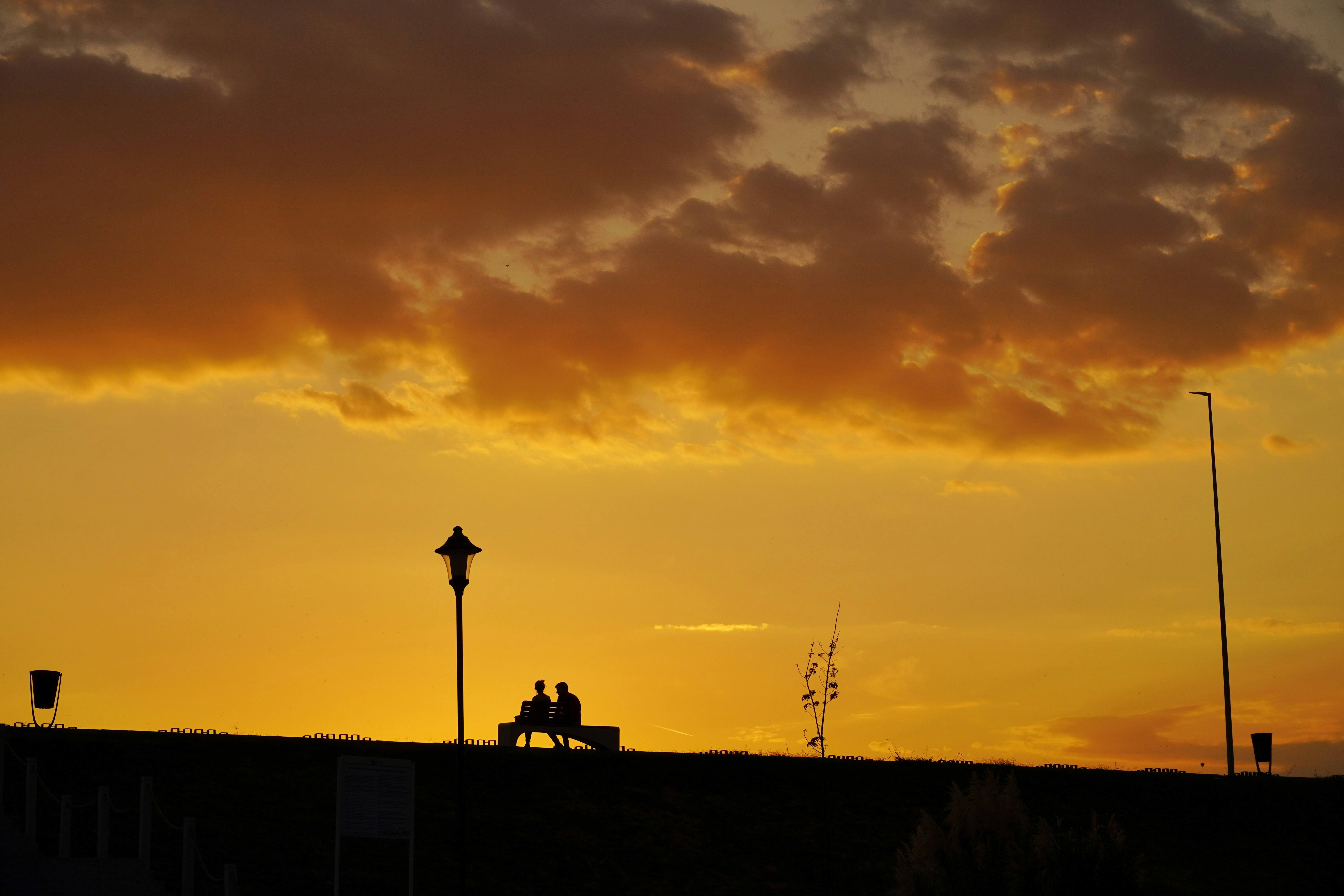 A person sitting on a bench watching the sun set photo – Free Bucharest ...