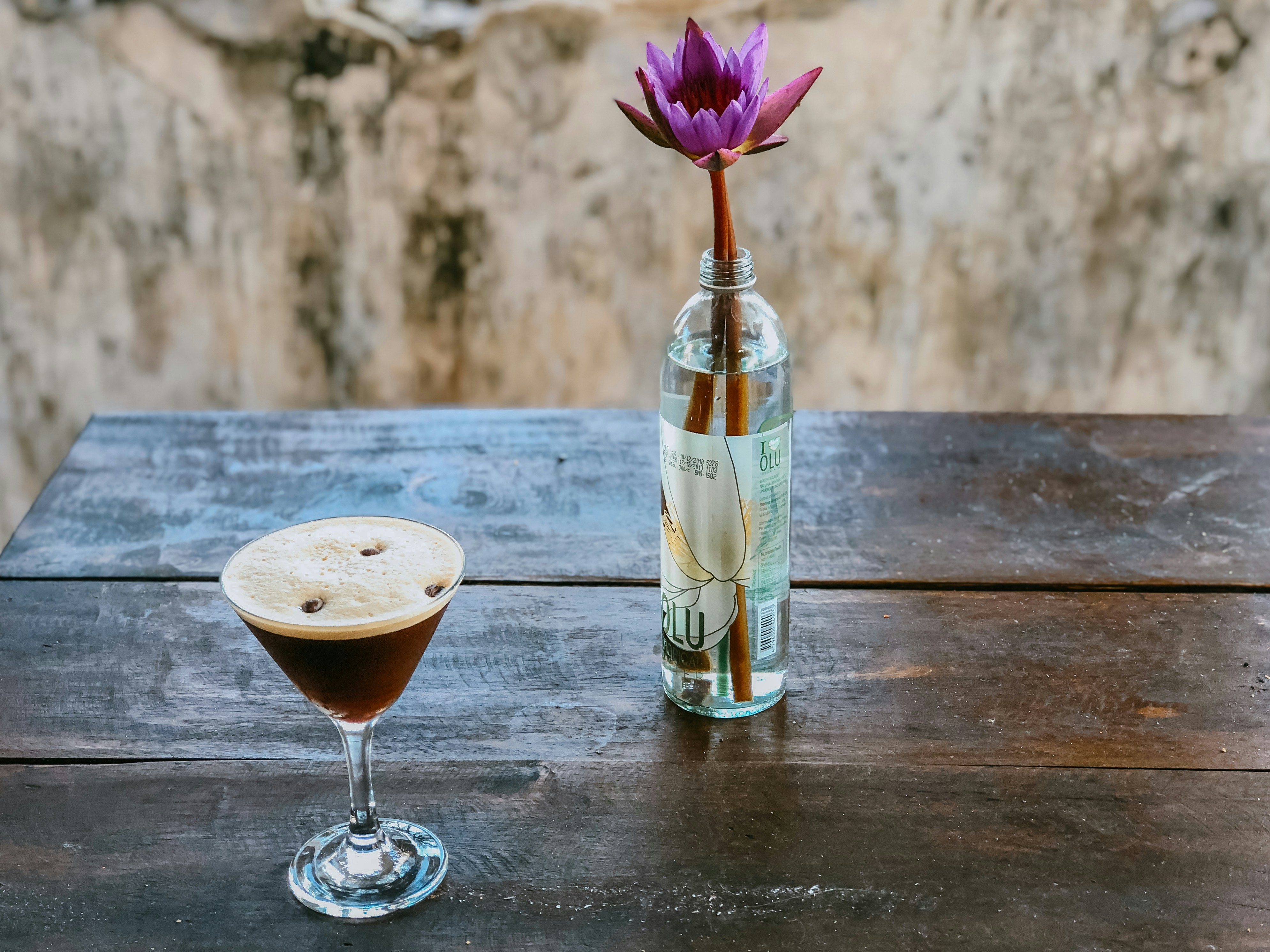 Bloom in a Bottle: Purple Lotus on a Weathered Table