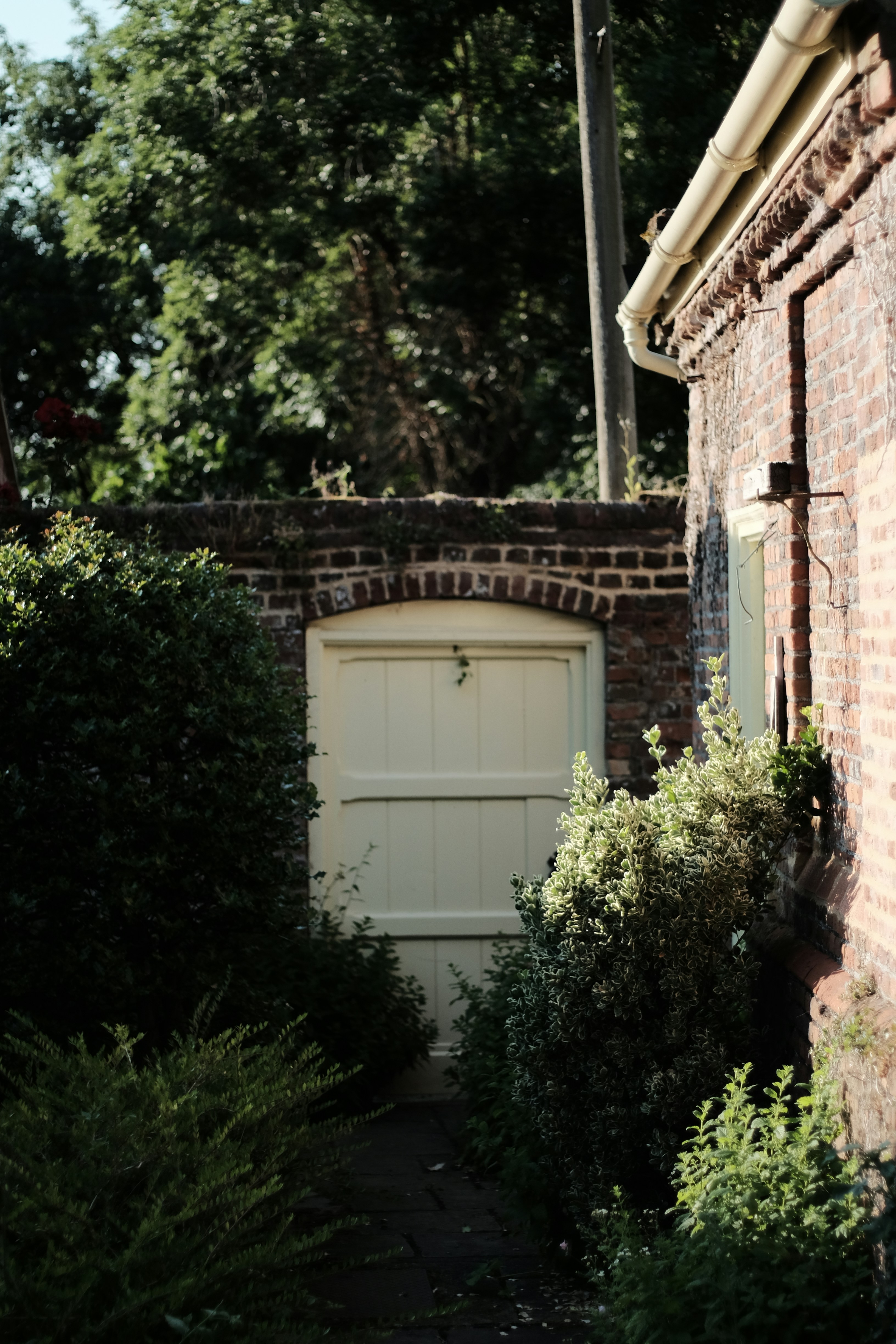 Cream Doorway at the End of a Brick-Lined Garden Alley
