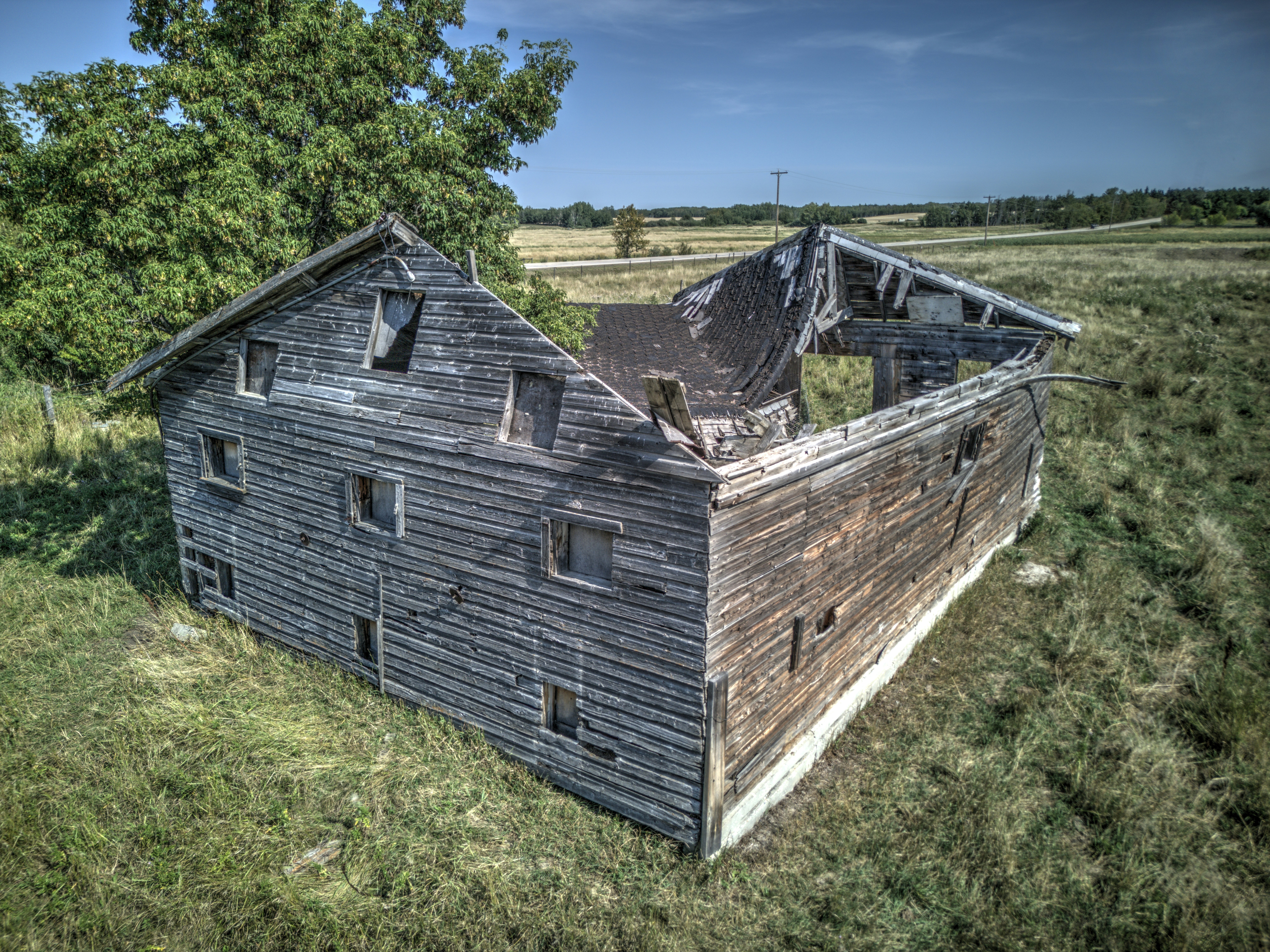 Colapsed House | An old wooden building sitting in the middle of a field