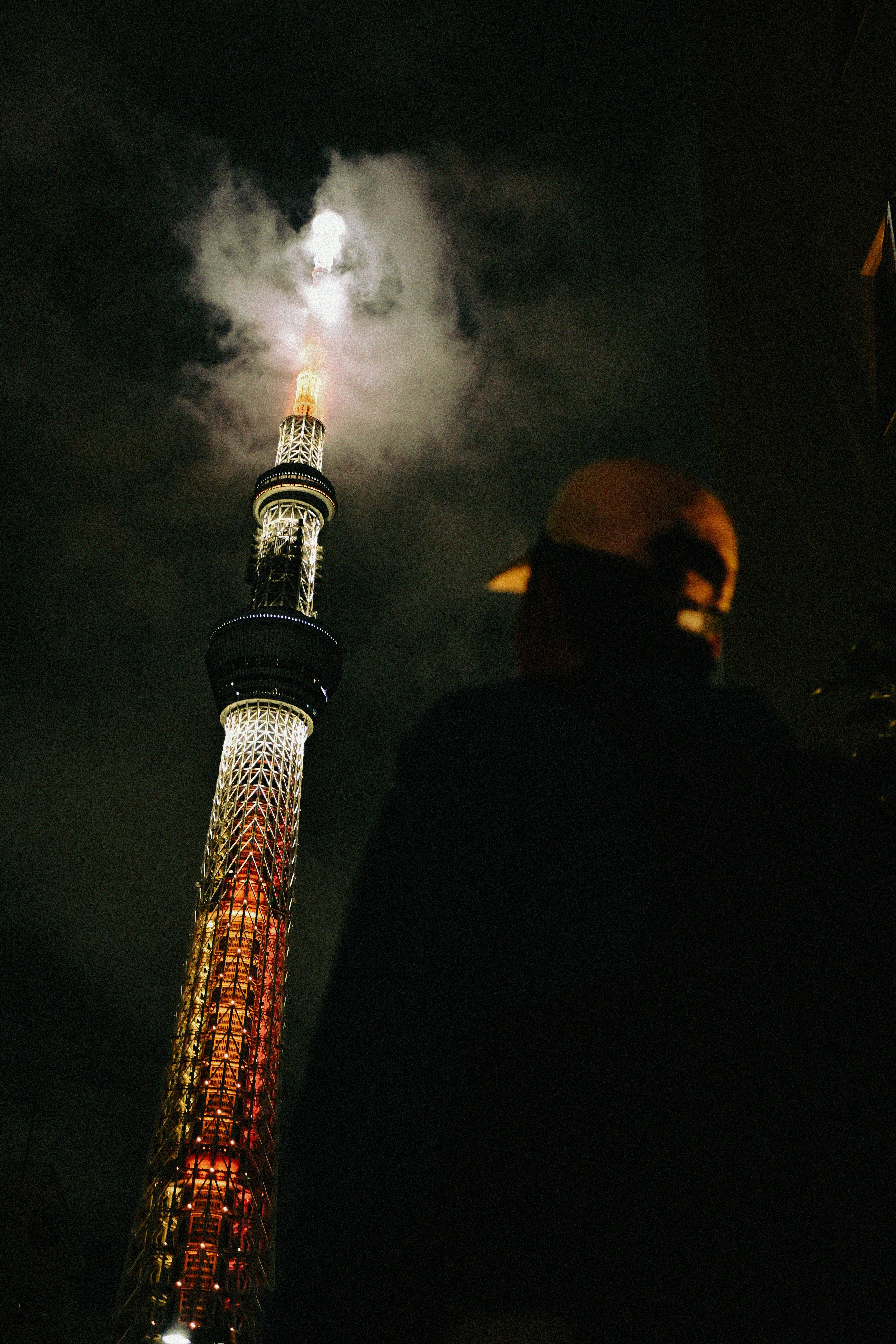 Tokyo Tower's Neon Lattice Reaches the Night Sky, Framed by a Shadowed Onlooker