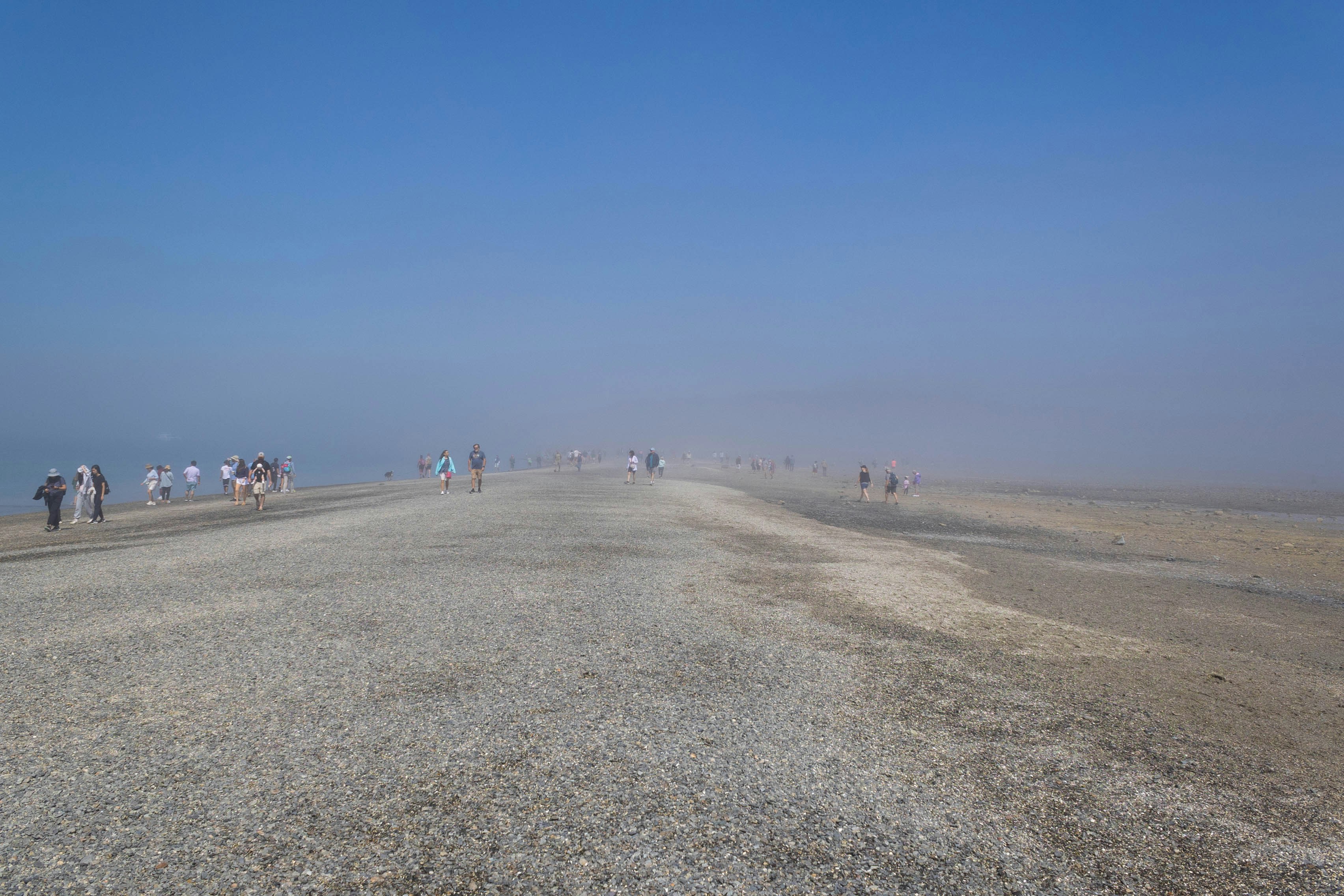 Misty Pebble Path: silhouettes head toward a pale horizon