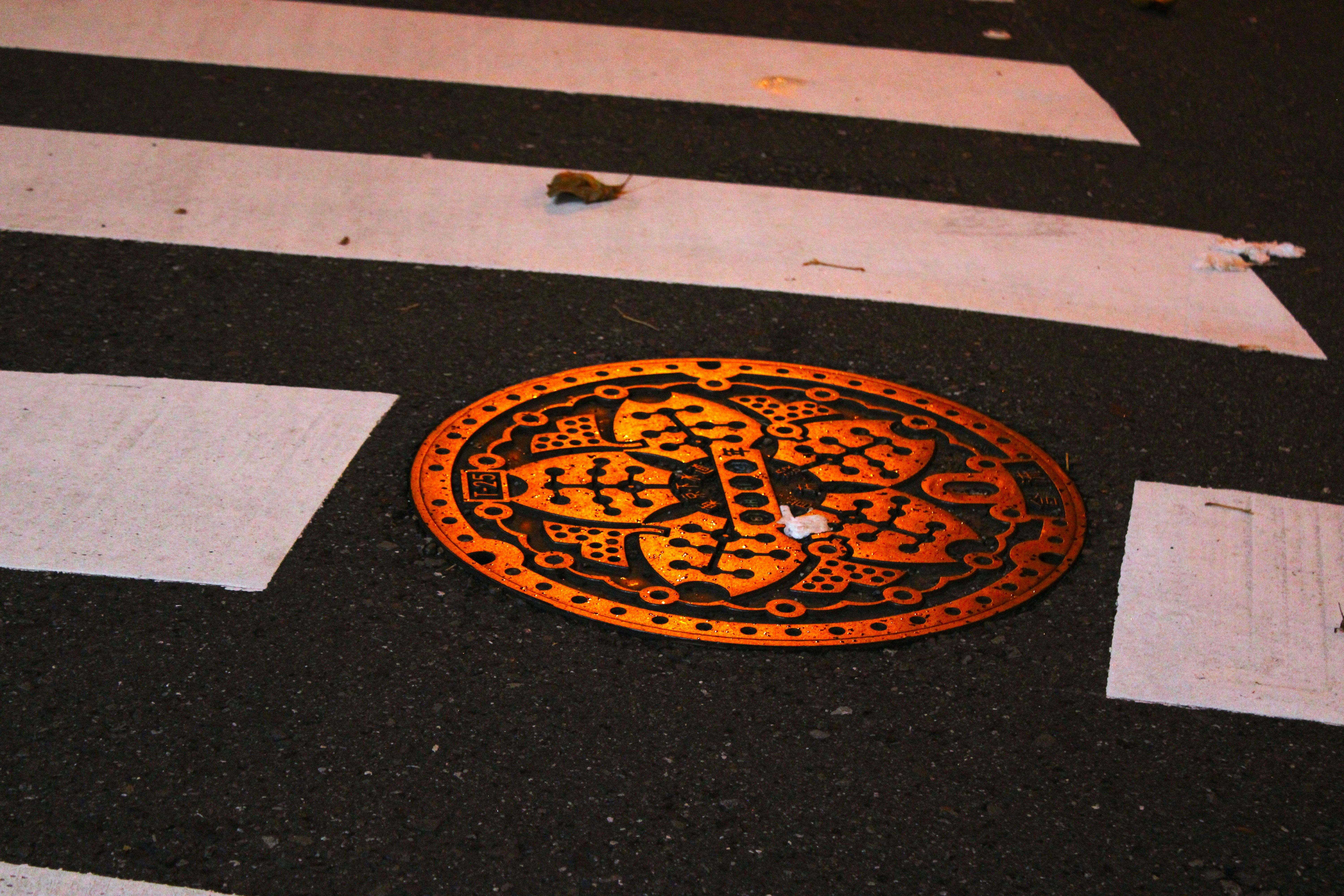 A manhole cover on the ground in the middle of the street photo – Free ...