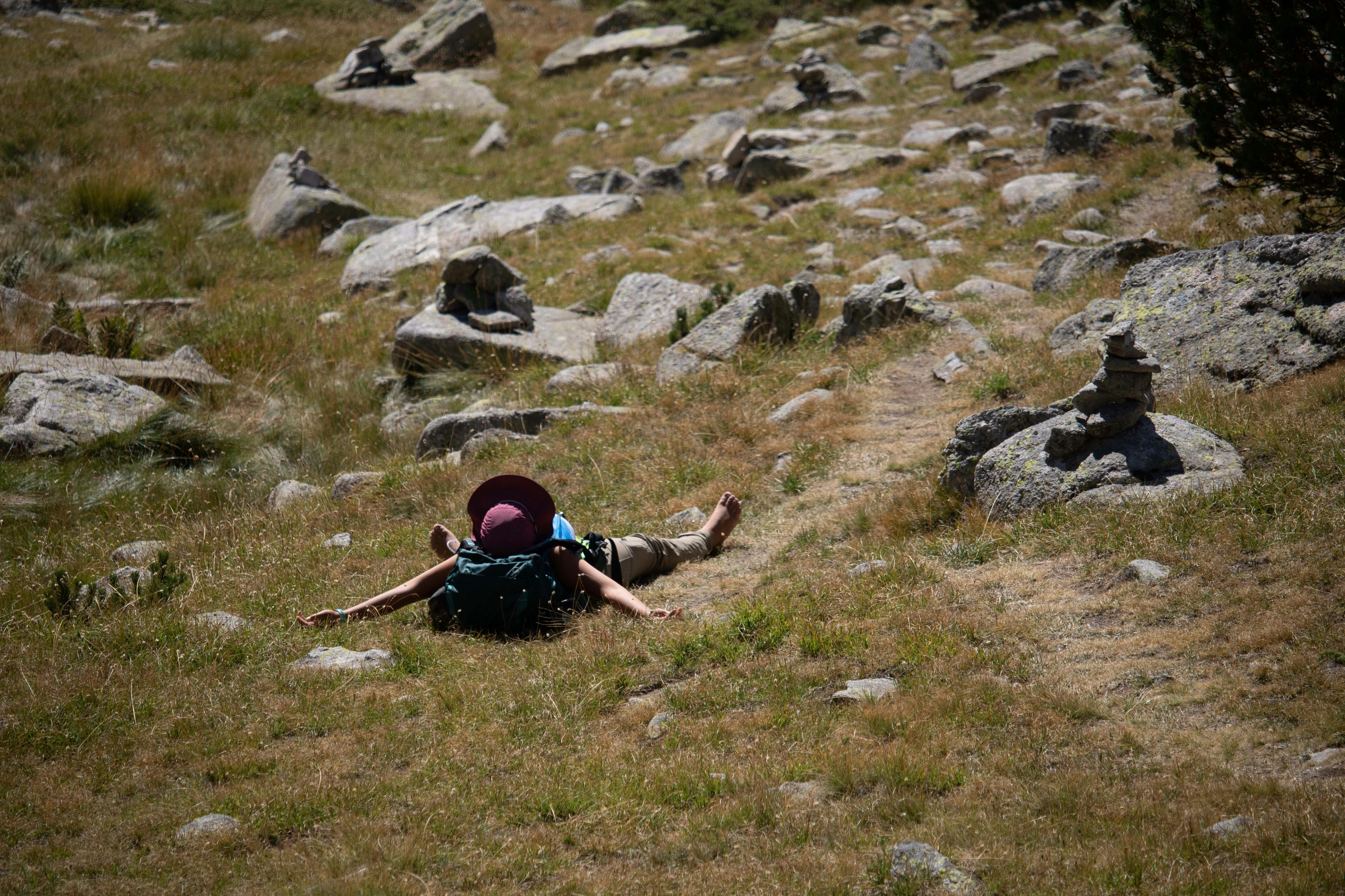 A person laying on the ground with a backpack photo – Free Rila ...