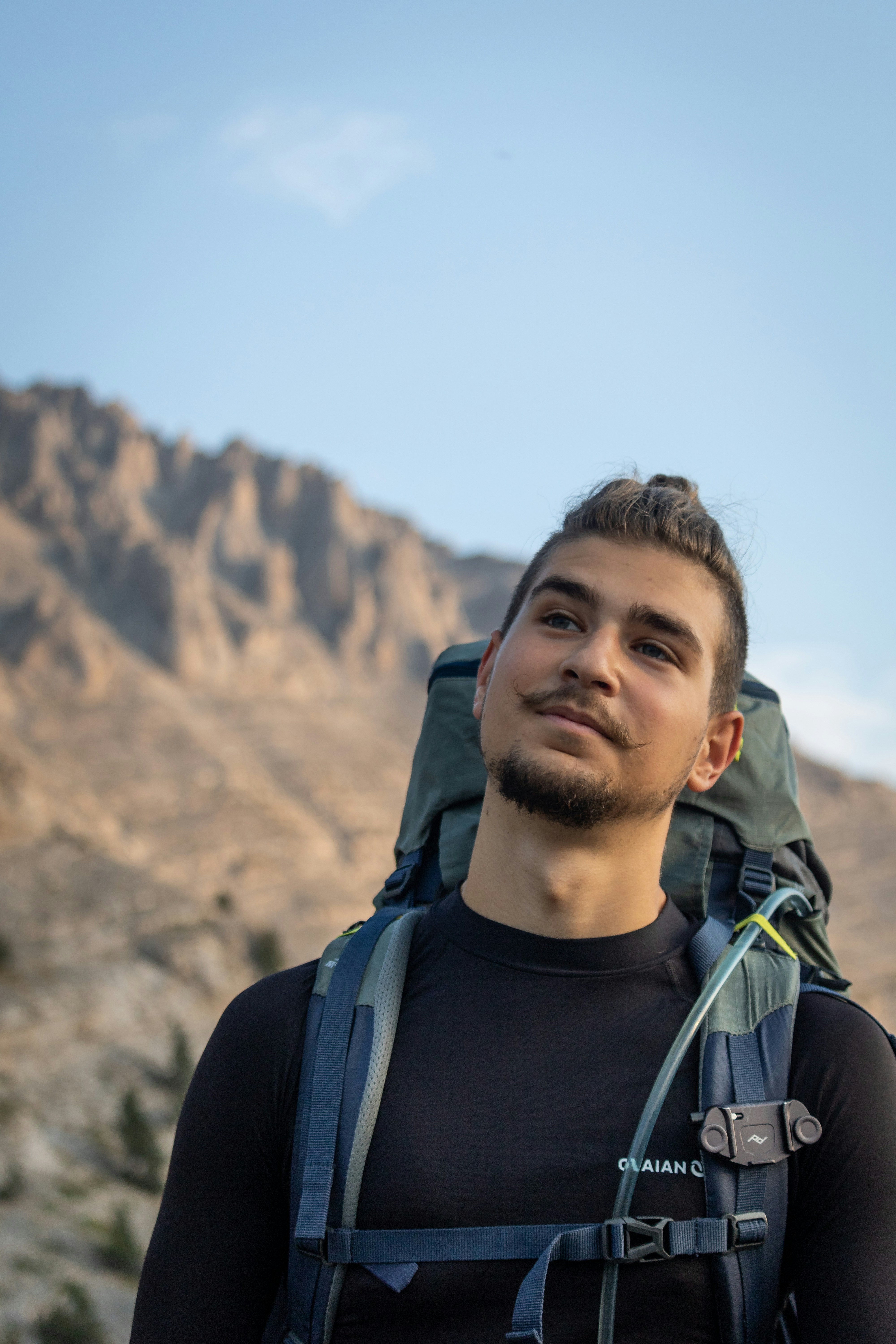 A man with a backpack standing in front of a mountain