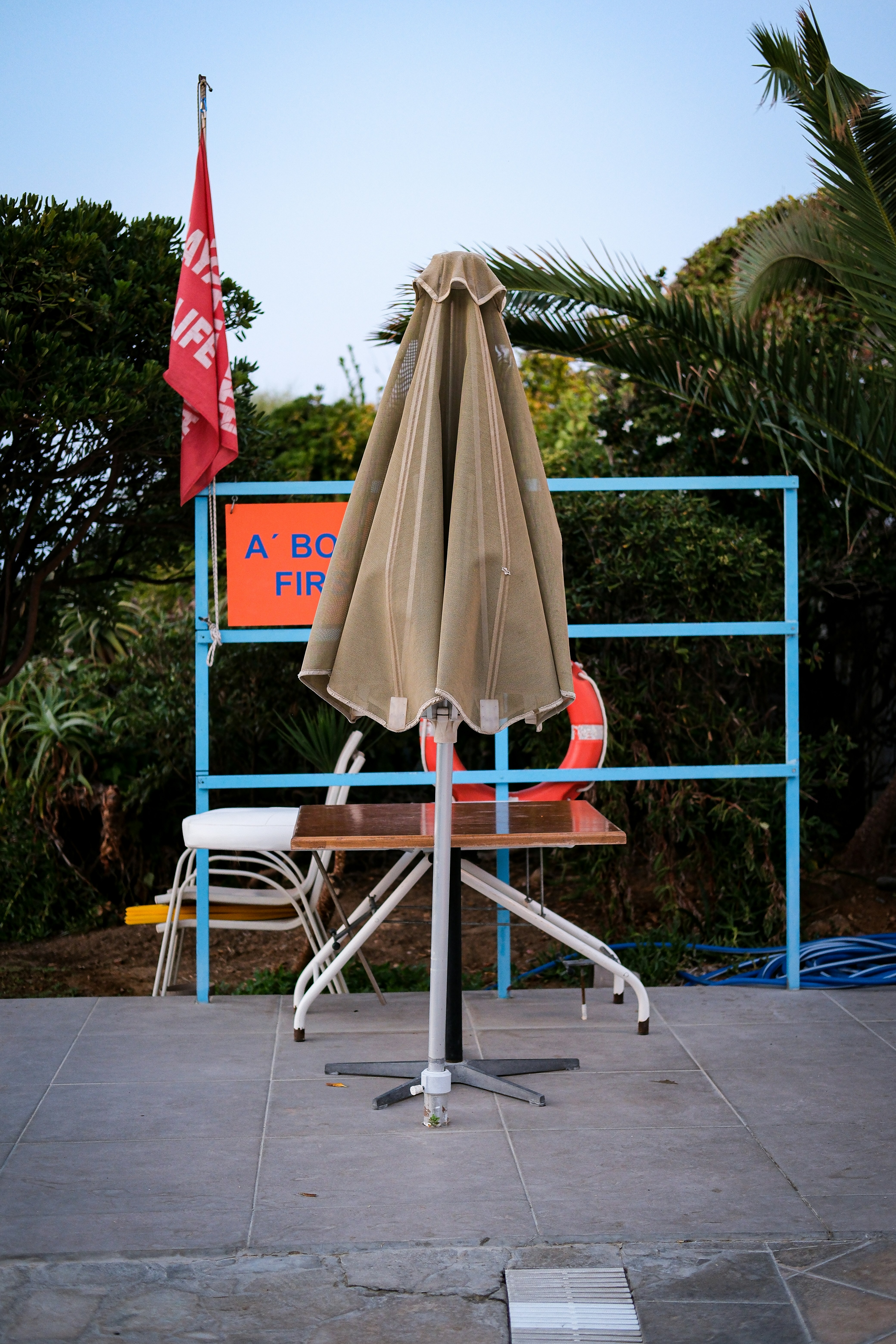 Closed Umbrella Over the Tiled Terrace Garden by the Pool