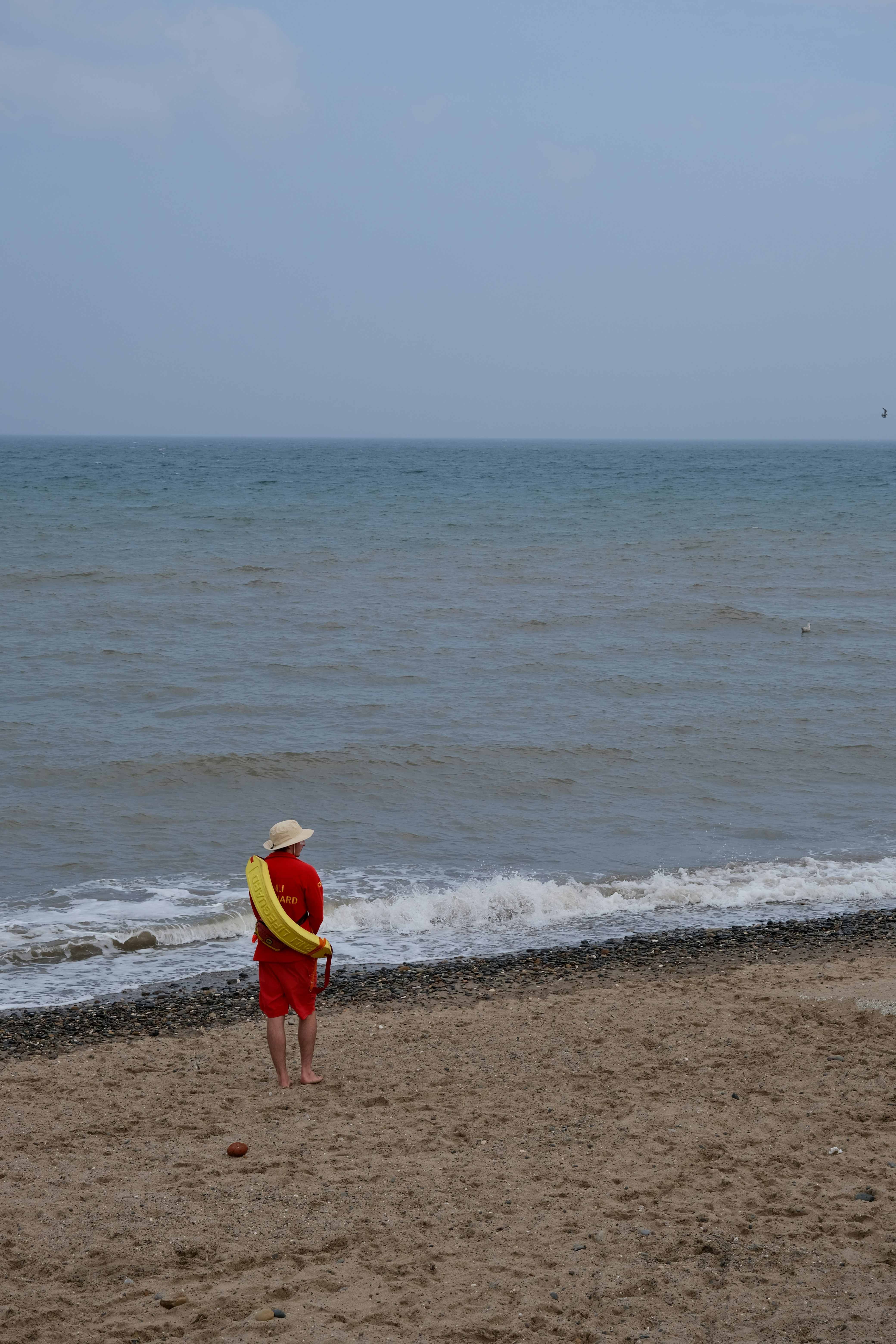 Red-Clad Child at the Shore with a Banana Float: A Quiet Seaside Moment