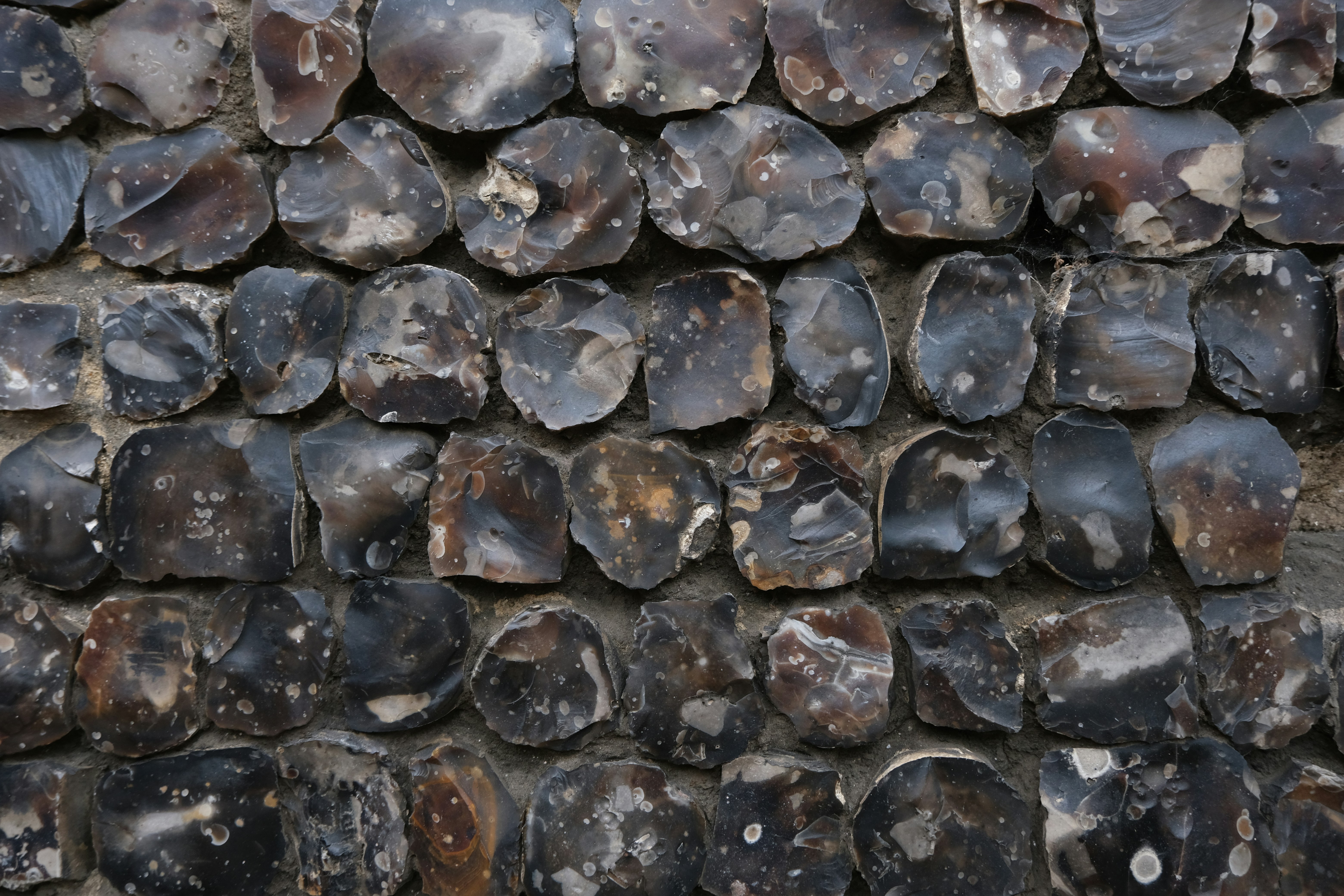Flint stones meticulously arranged in a traditional wall pattern, showcasing their natural colors and textures.
