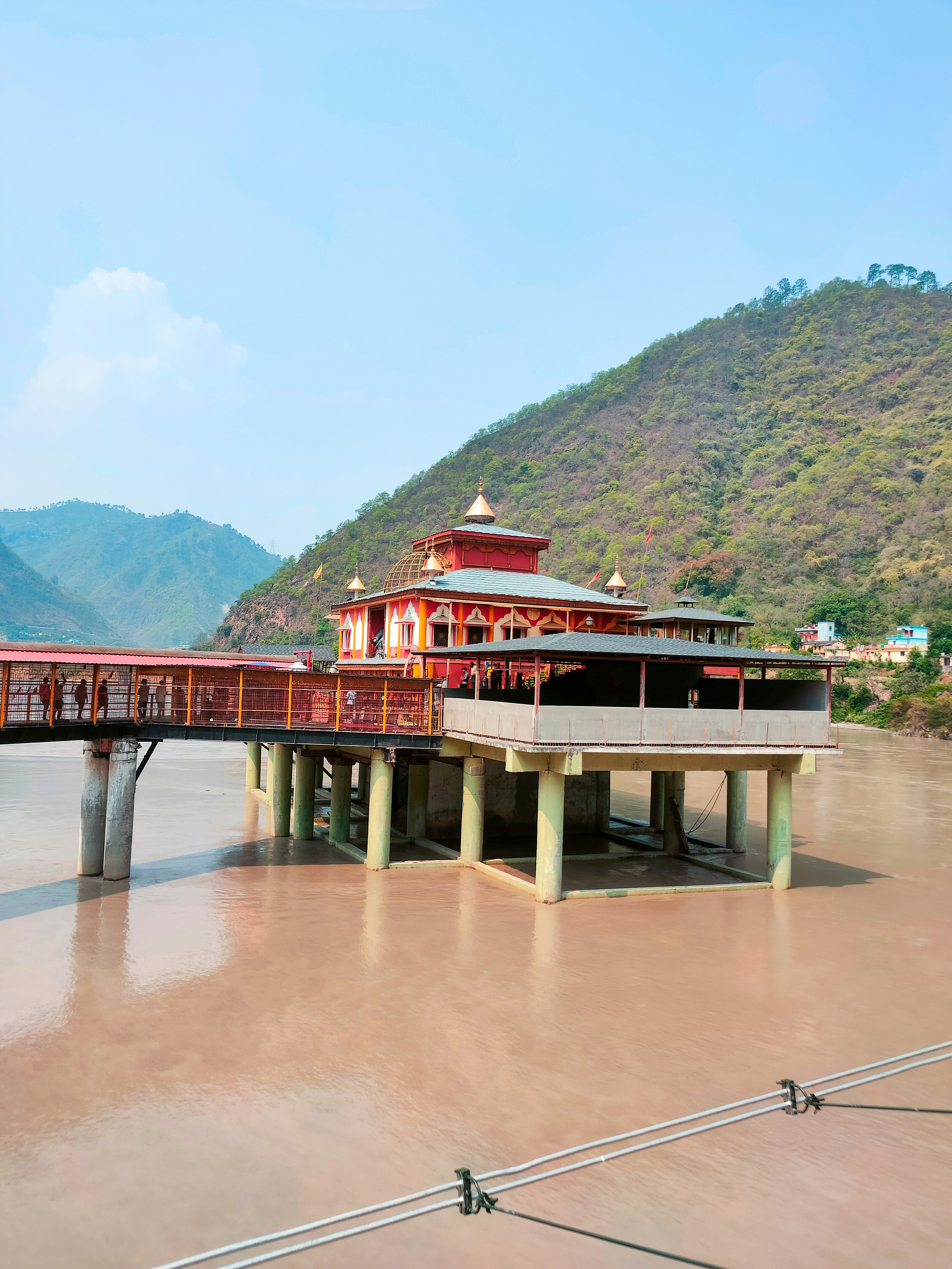 Red-Roofed Temple on Stilts Over a Muddy Riverside