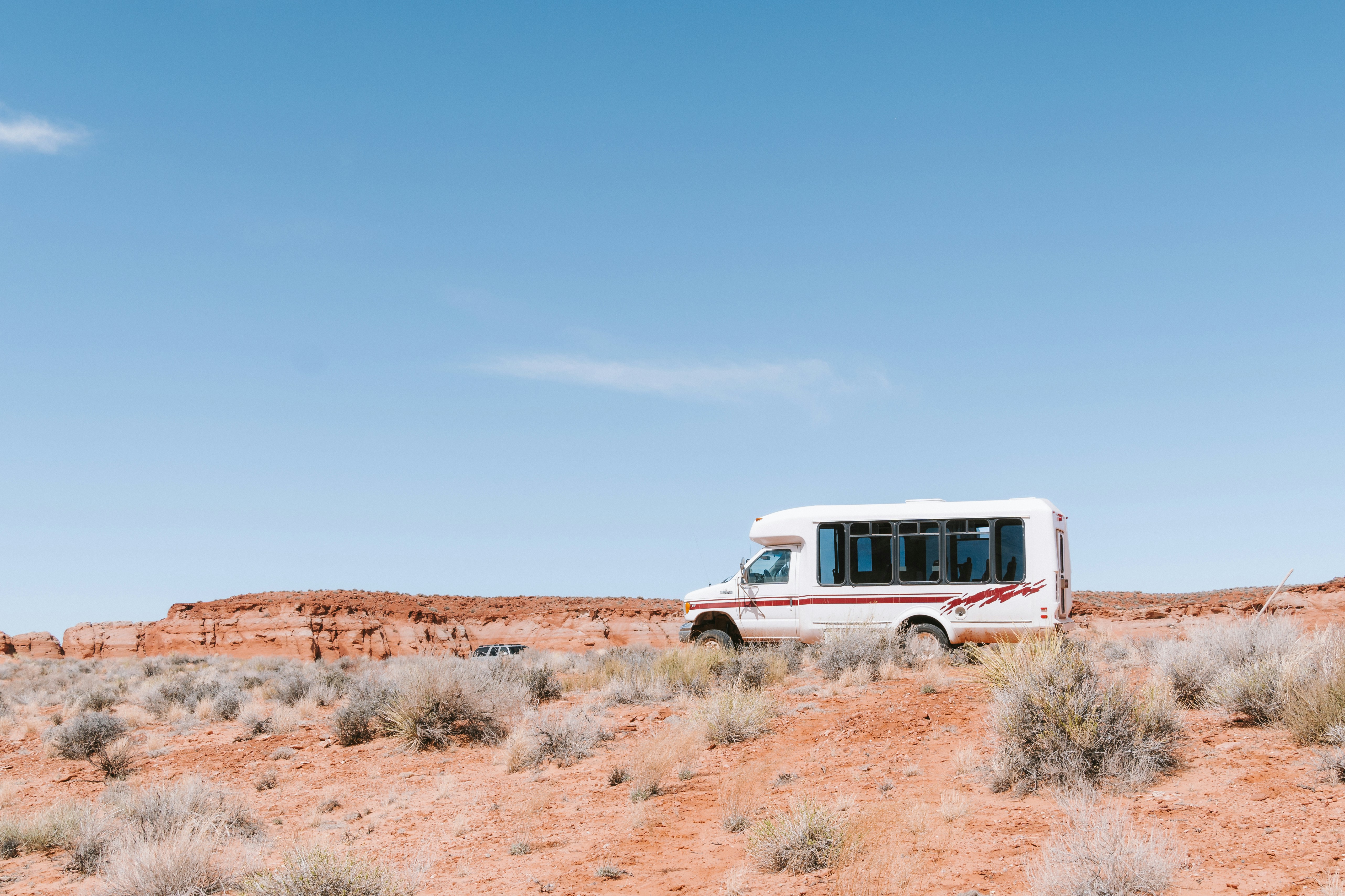 A white bus driving through a desert landscape photo – Free Ground ...