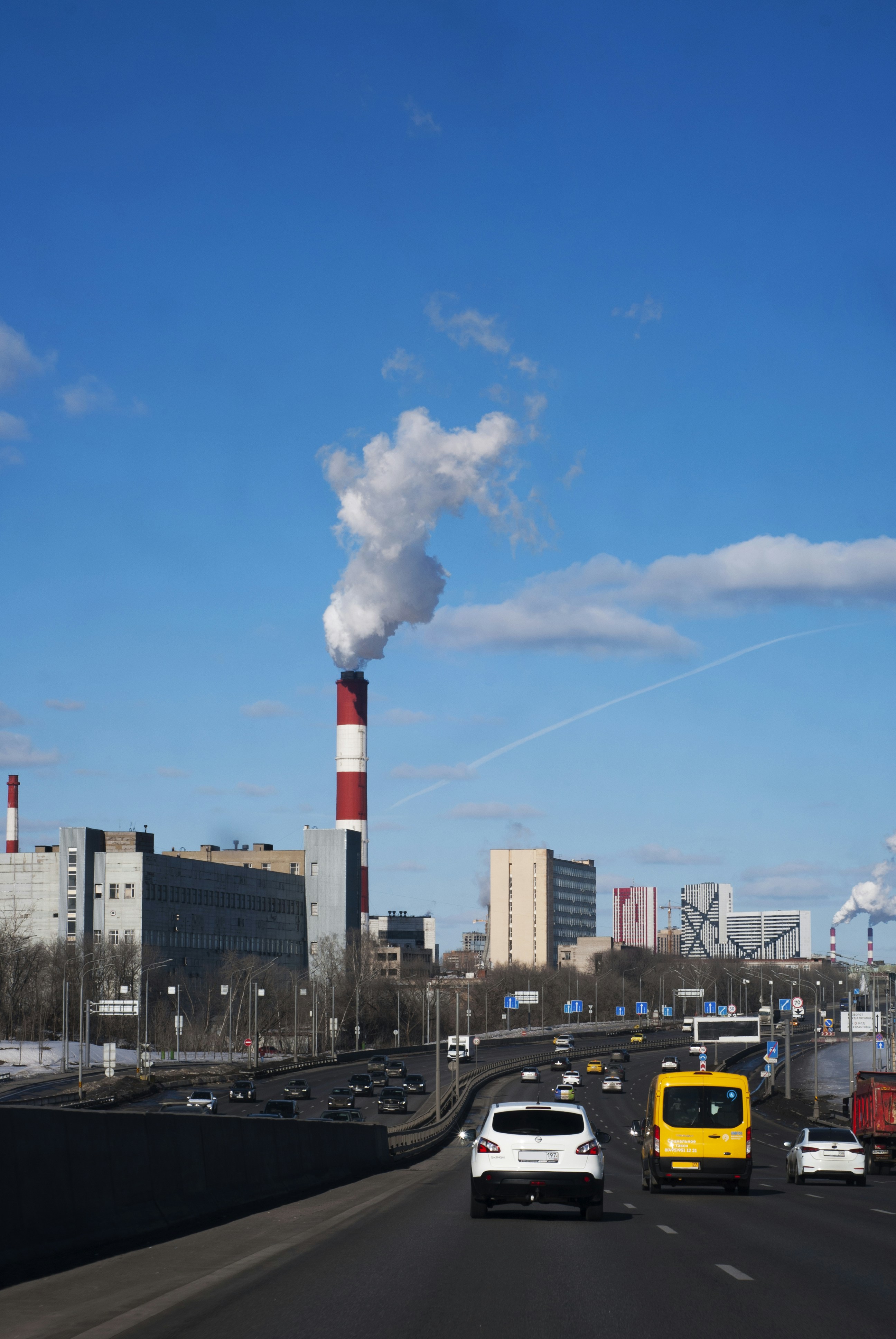 Chimney City Beacon: Steam Rises Over a Busy Highway Under a Bright Blue Sky