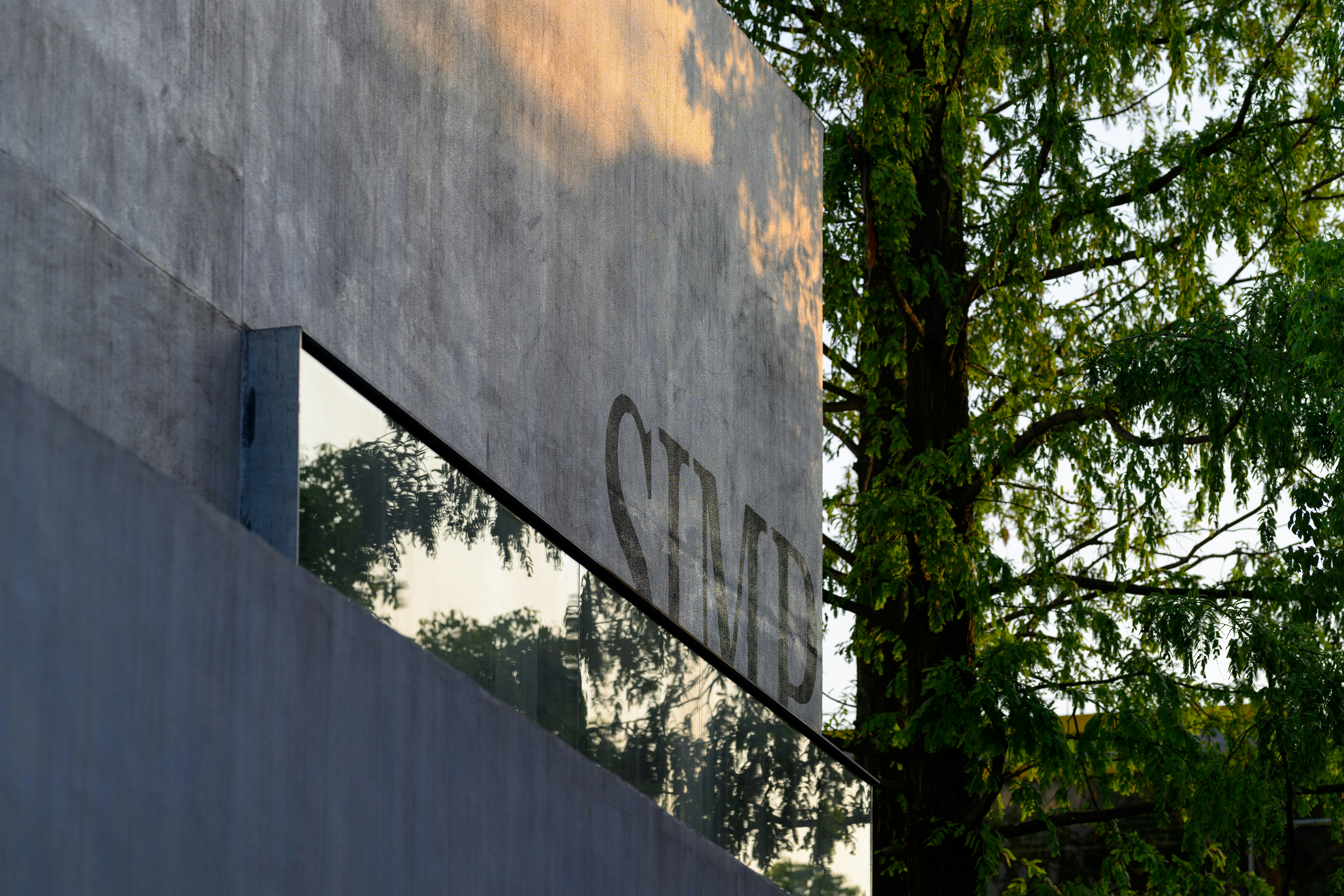 Diagonal Glass Slice on a Weathered Concrete Facade