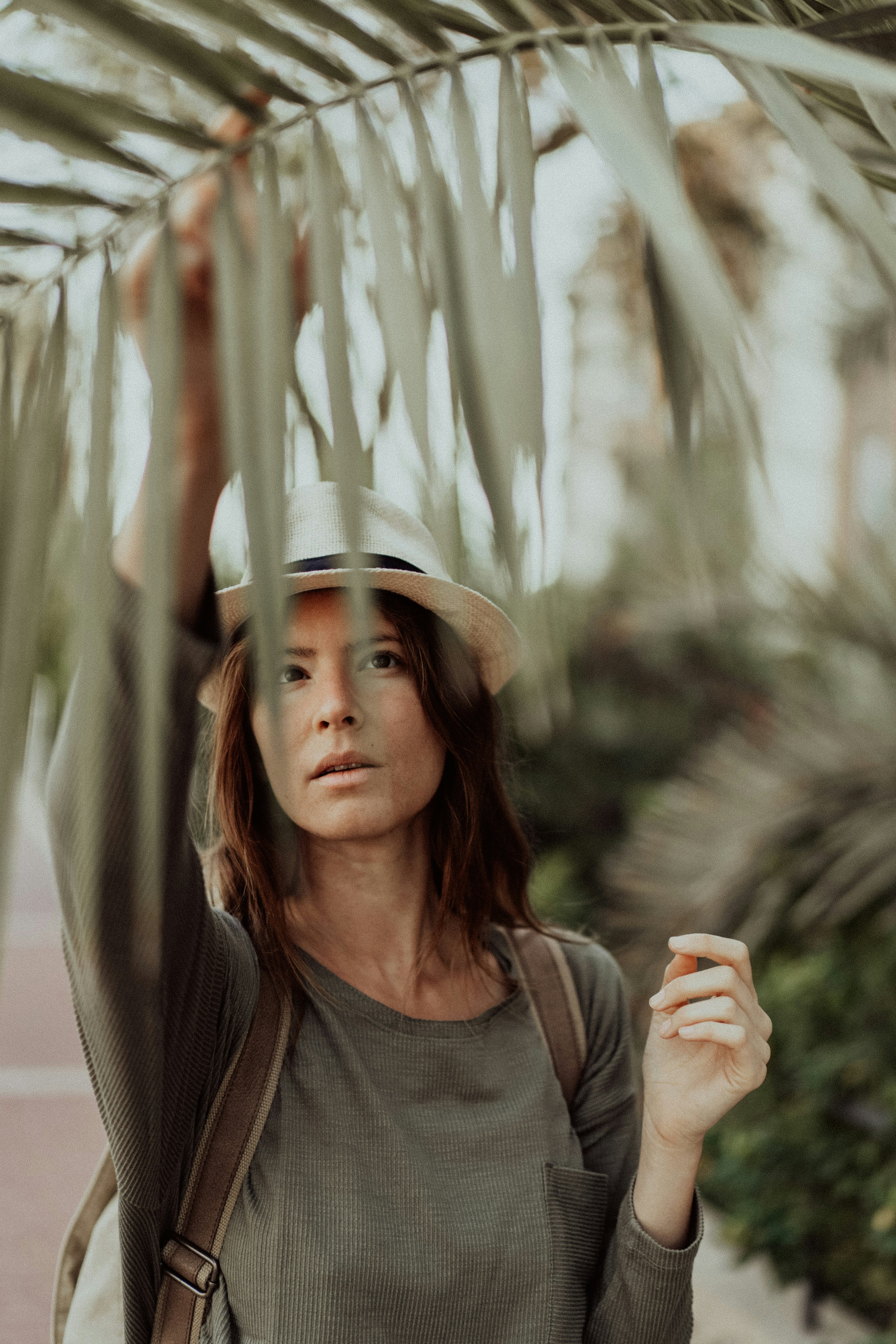Glimpse Through Palm Fronds: A Quiet Portrait in Soft Light