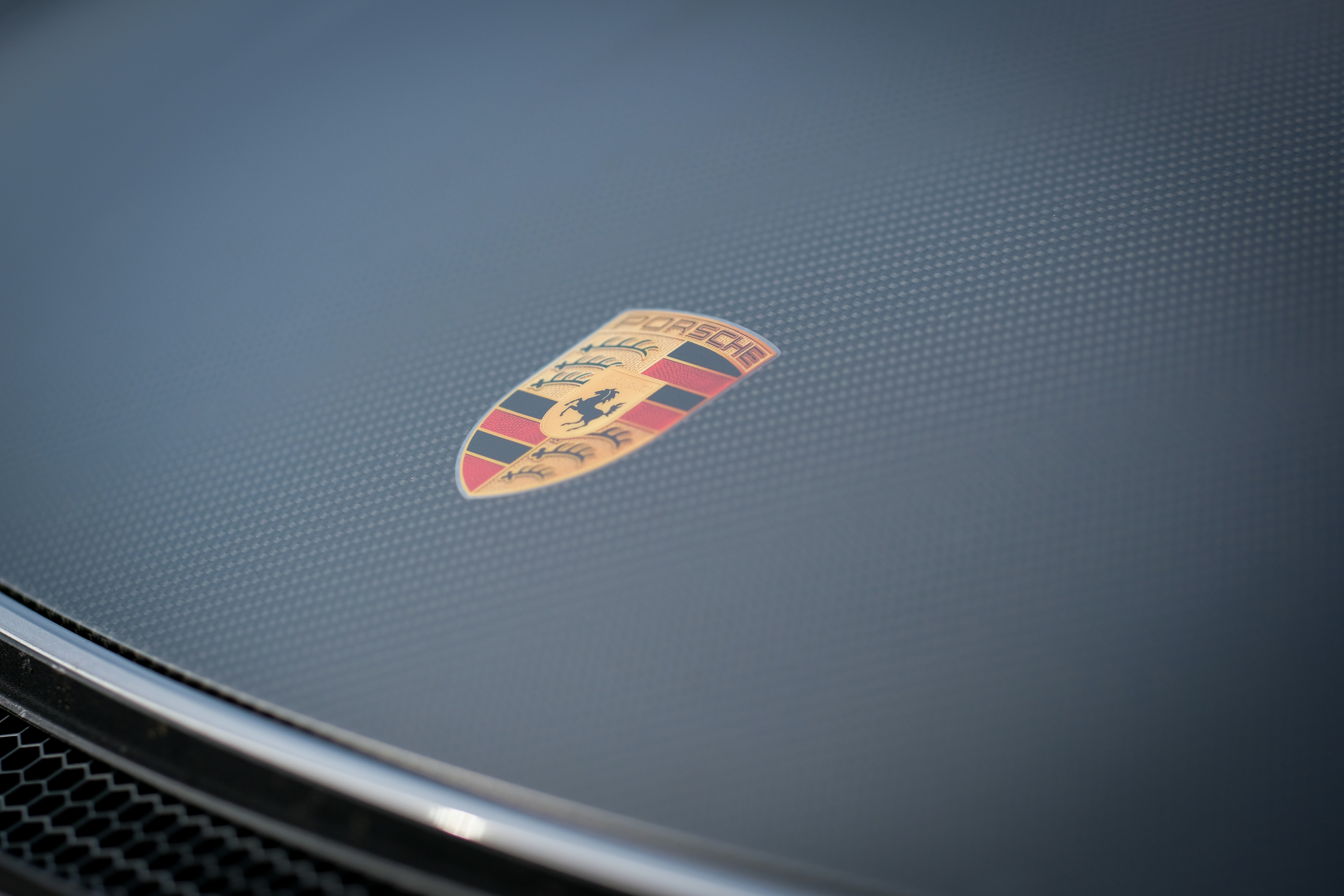 Emblem in Focus: Porsche Crest on a Textured Hood