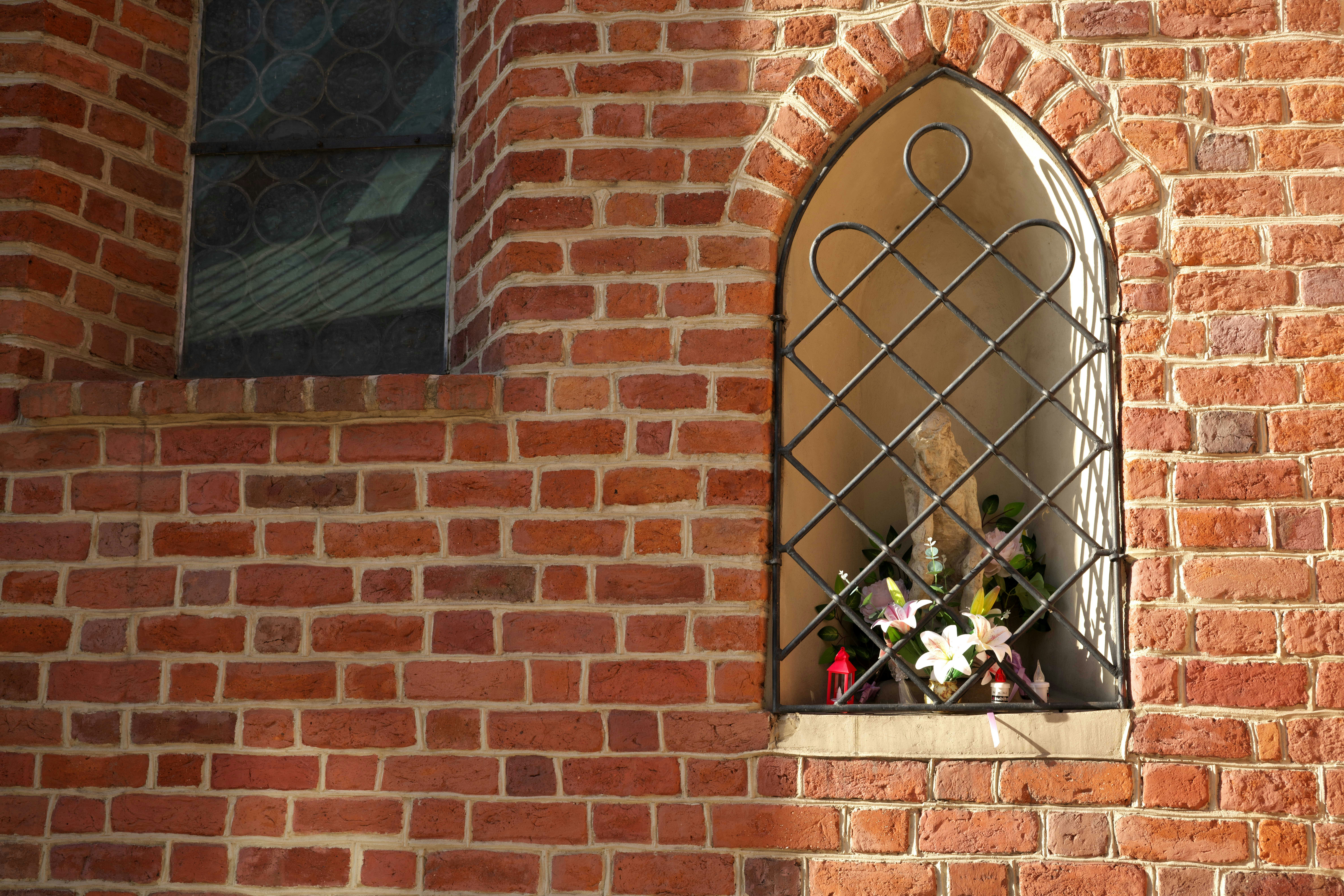 Arched Window Bloom: Flowers in a Brick Facade