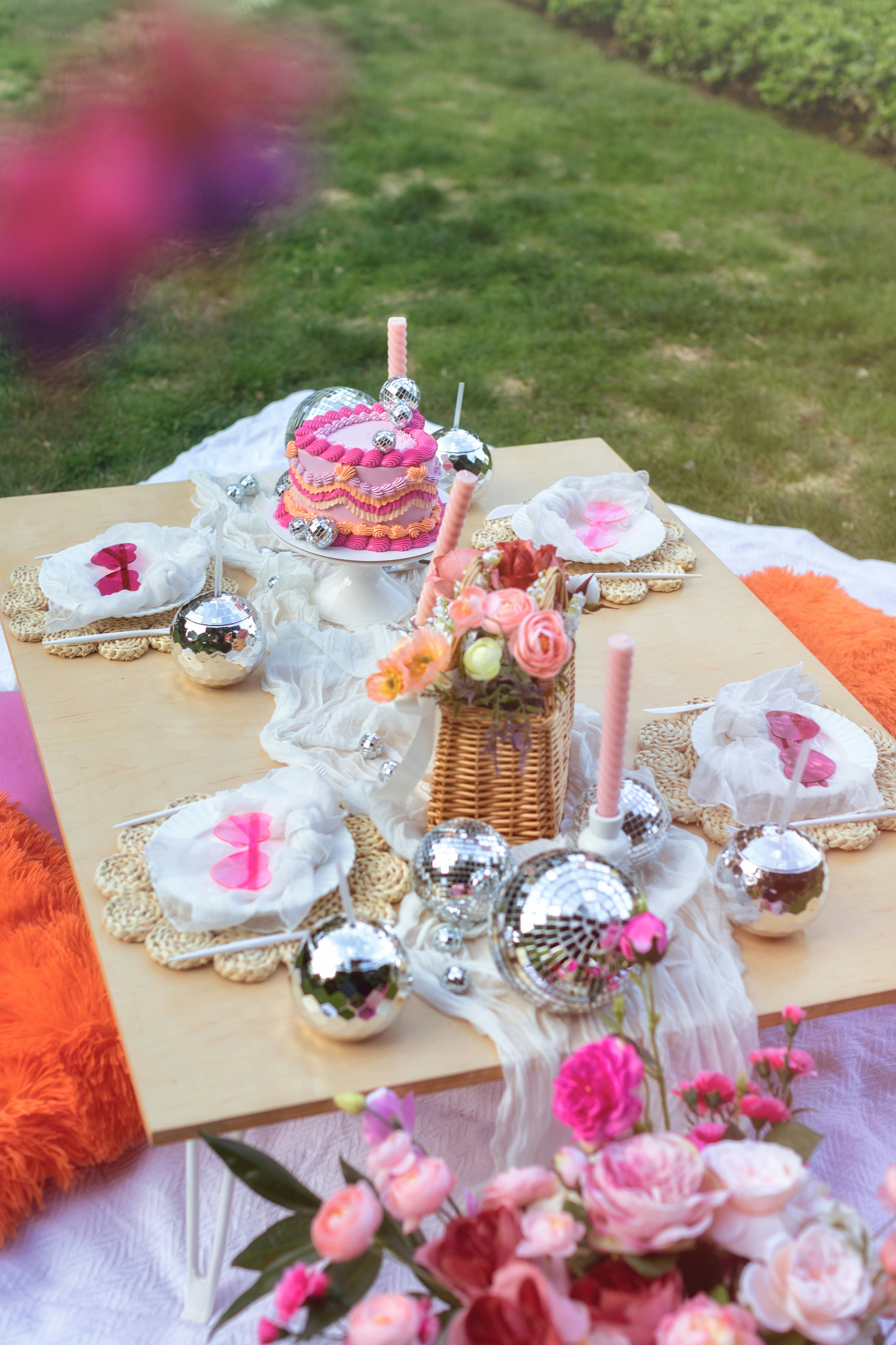 Pastel Picnic: A Cake, Florals, and Mirror Orbs on a Sunlit Table